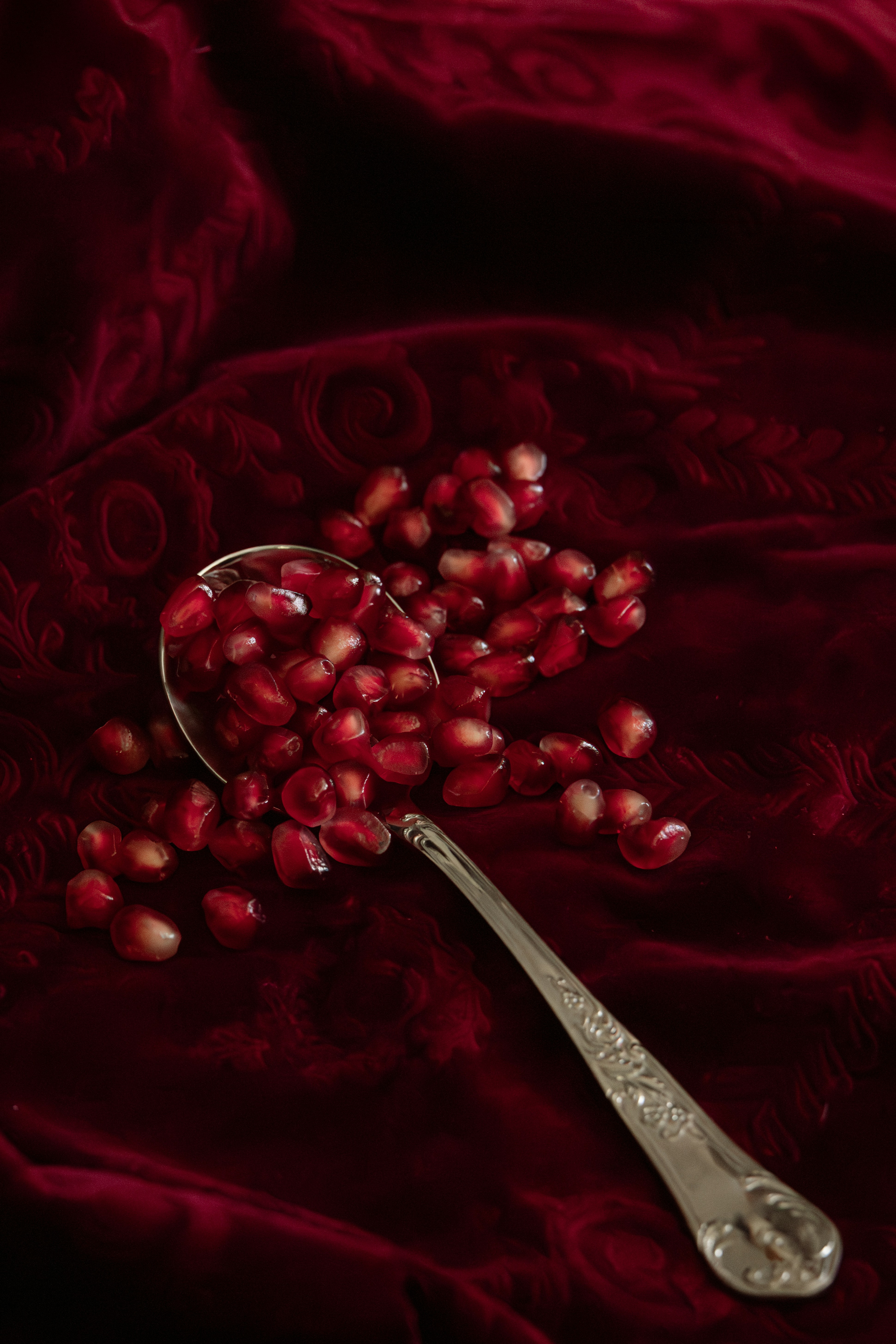Crimson Harvest: Pomegranate Seeds Spilled from a Silver Spoon