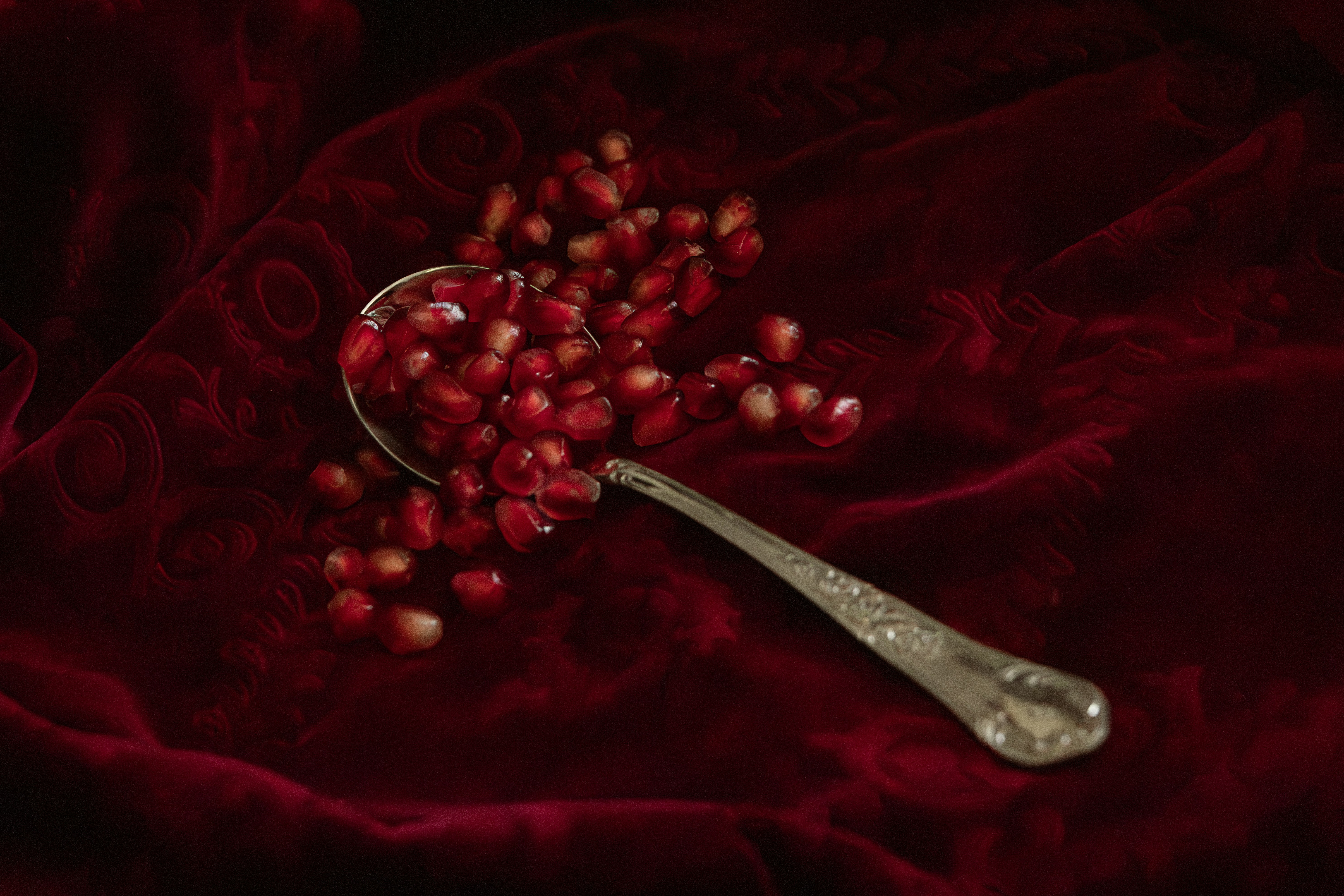 Crimson Berries on a Silver Spoon Against Velvet Night
