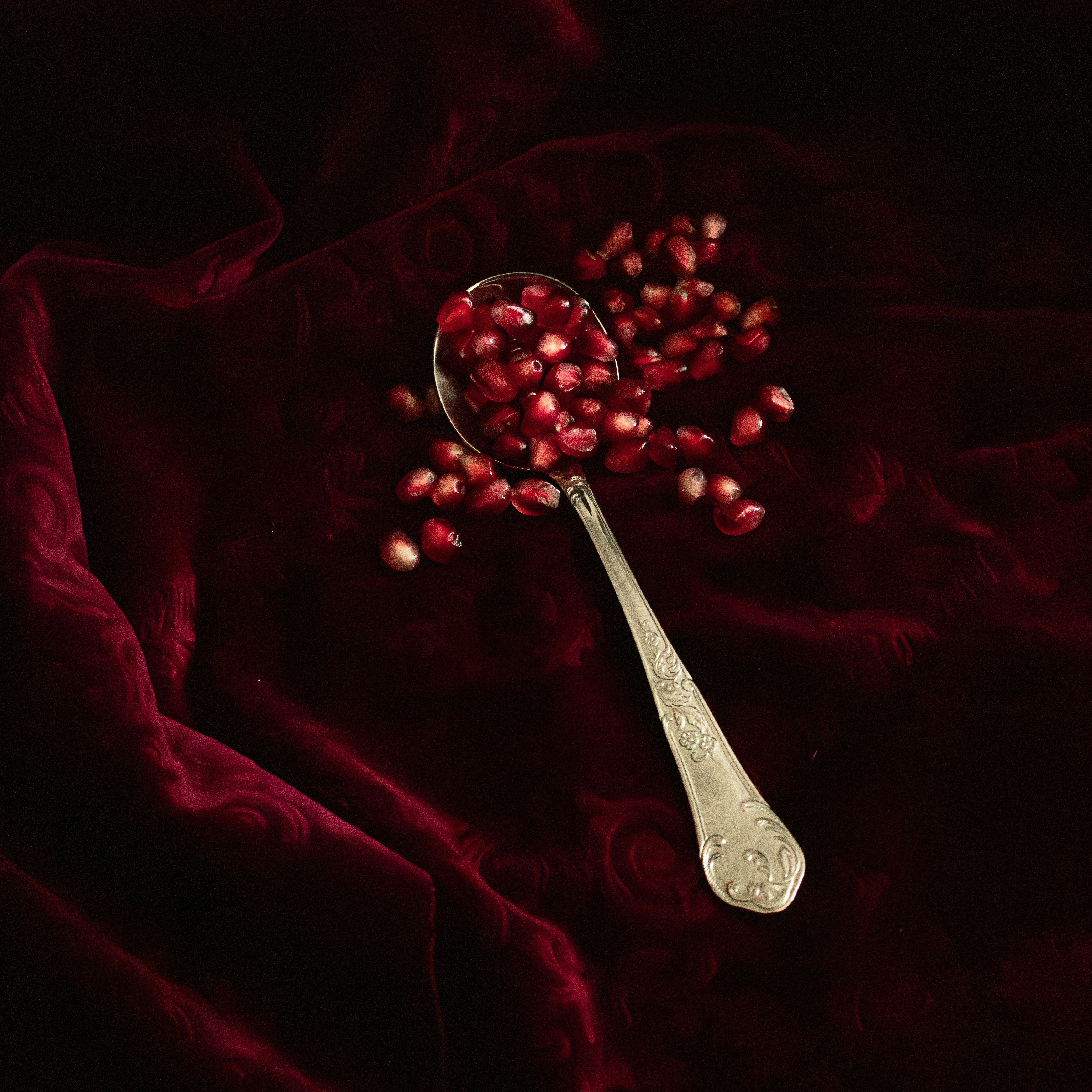 Crimson Scatter: A Silver Spoon of Pomegranate Remnants on Velvet Night