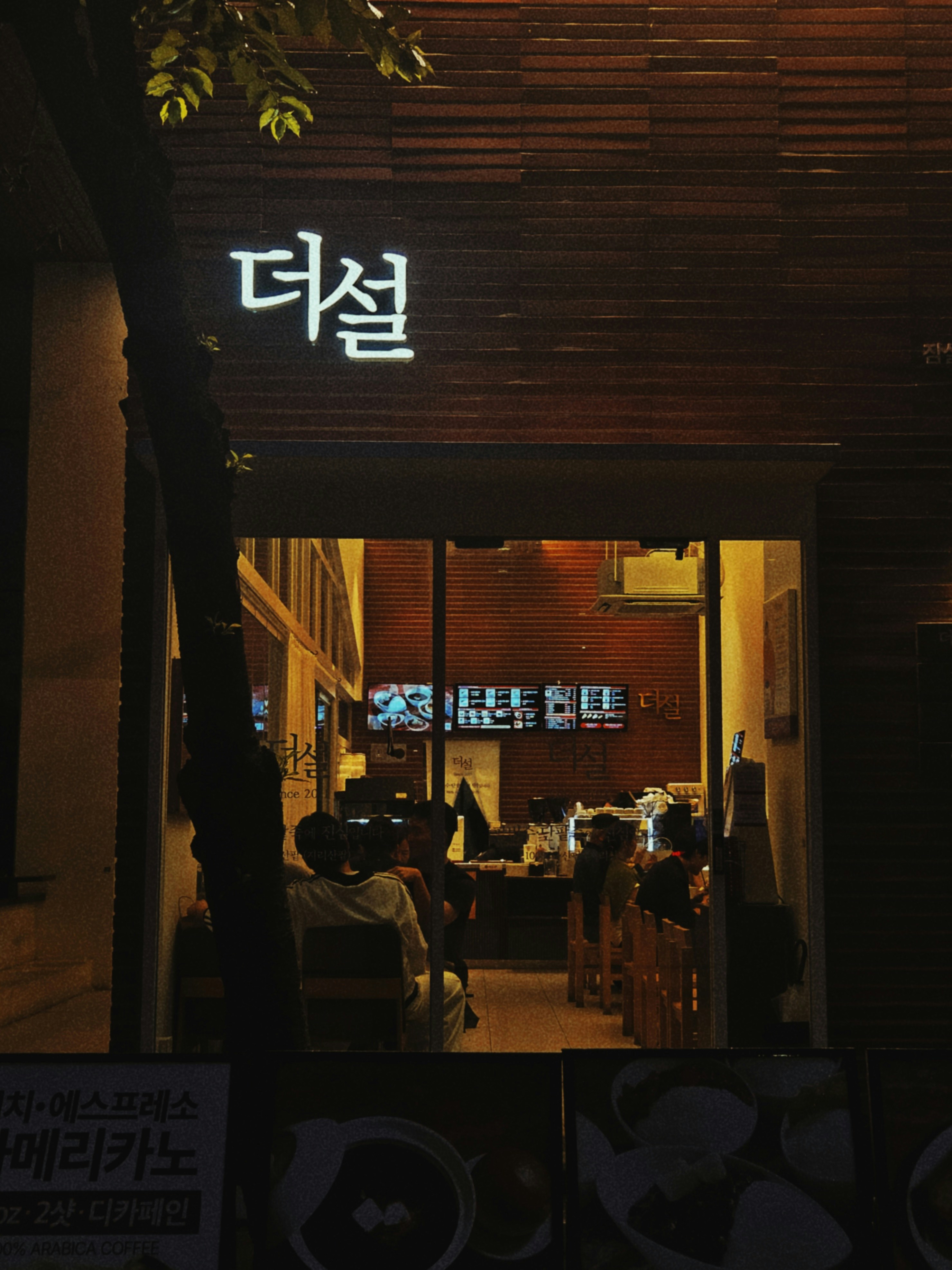 Neon Sign and Warm Interior: Nighttime Café Through Glass Front