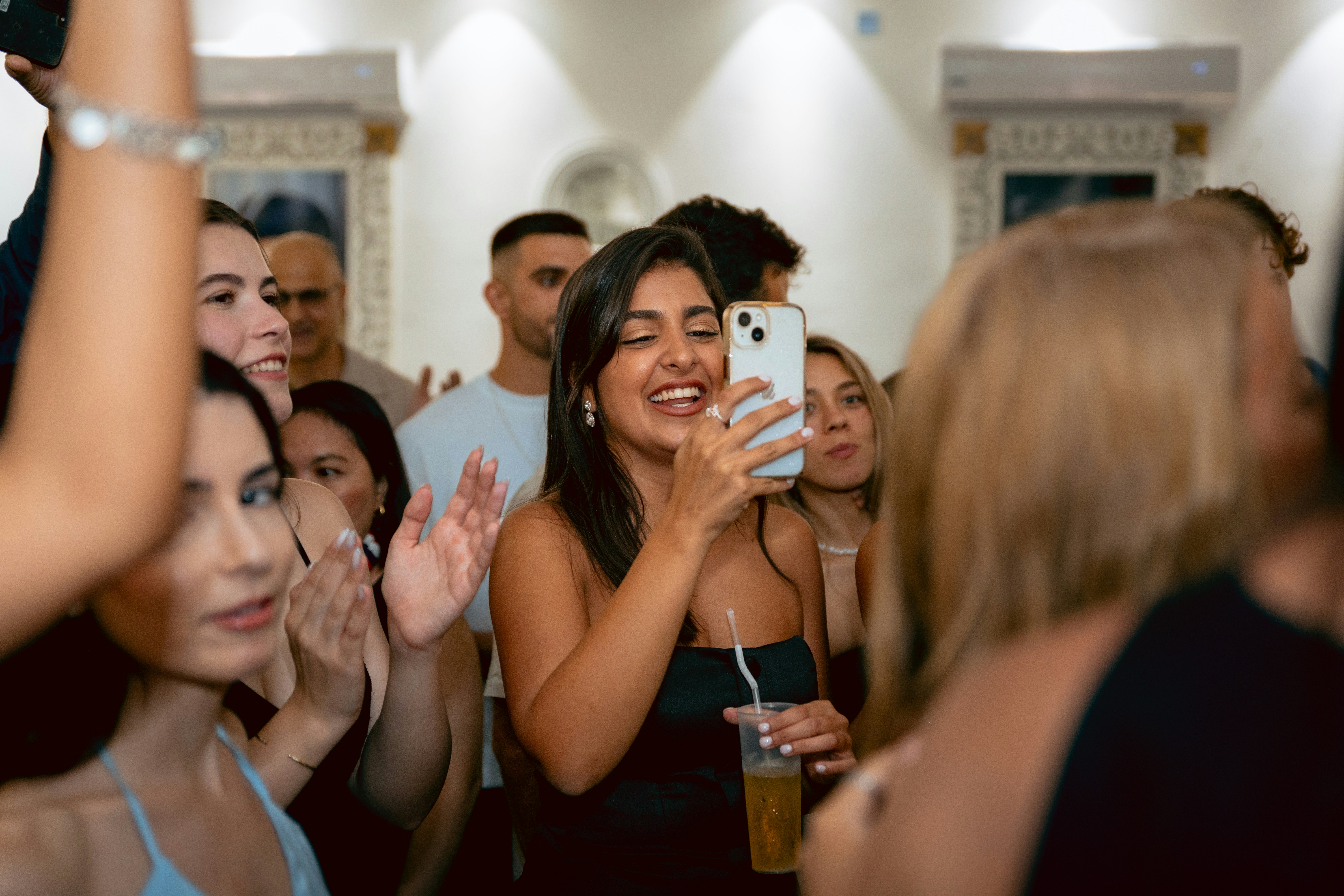 Center of celebration: a smiling woman with a phone at a crowded party