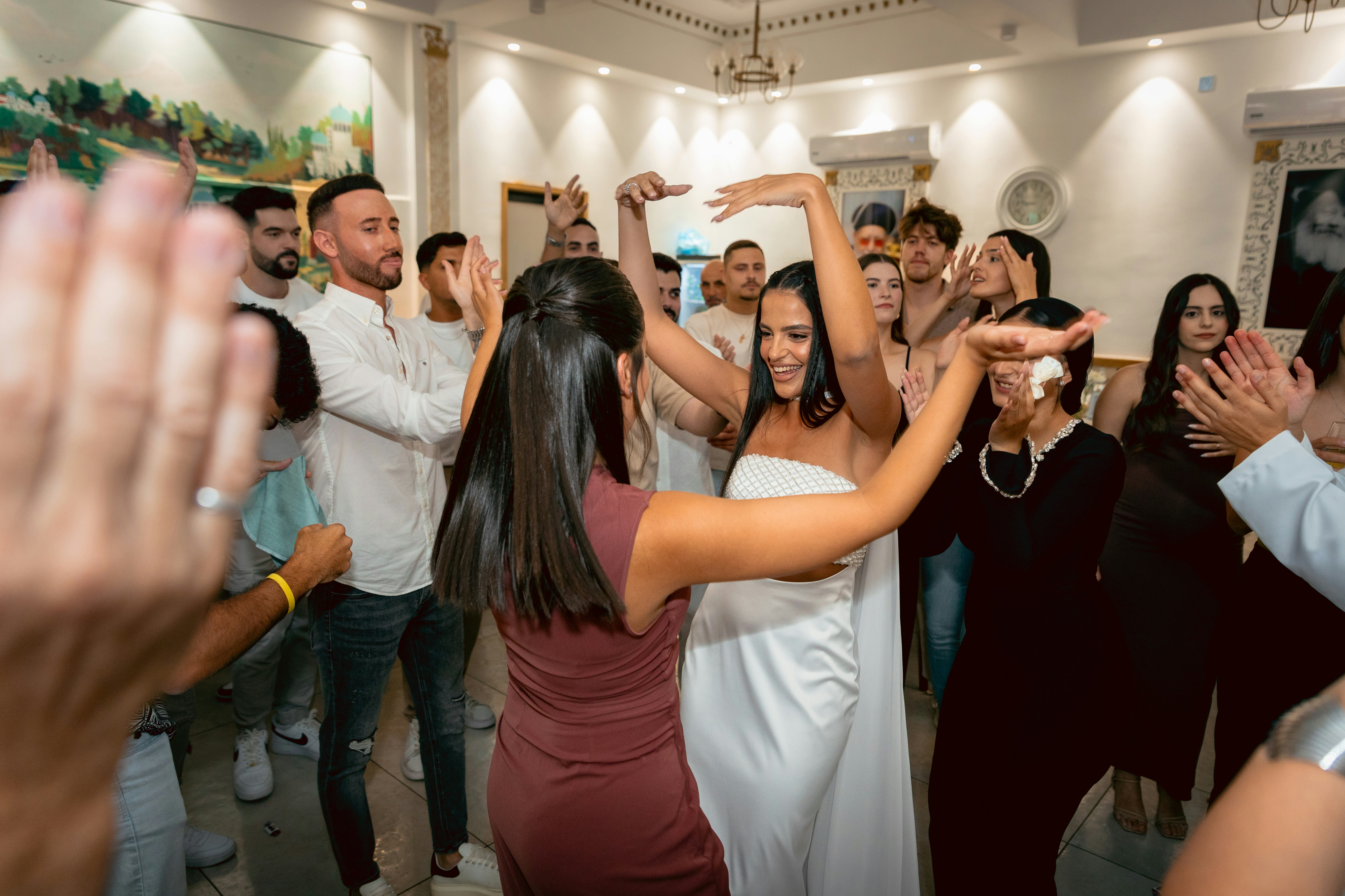 Bride in White Shares a Joyful Dance Amid a Lively Wedding Circle