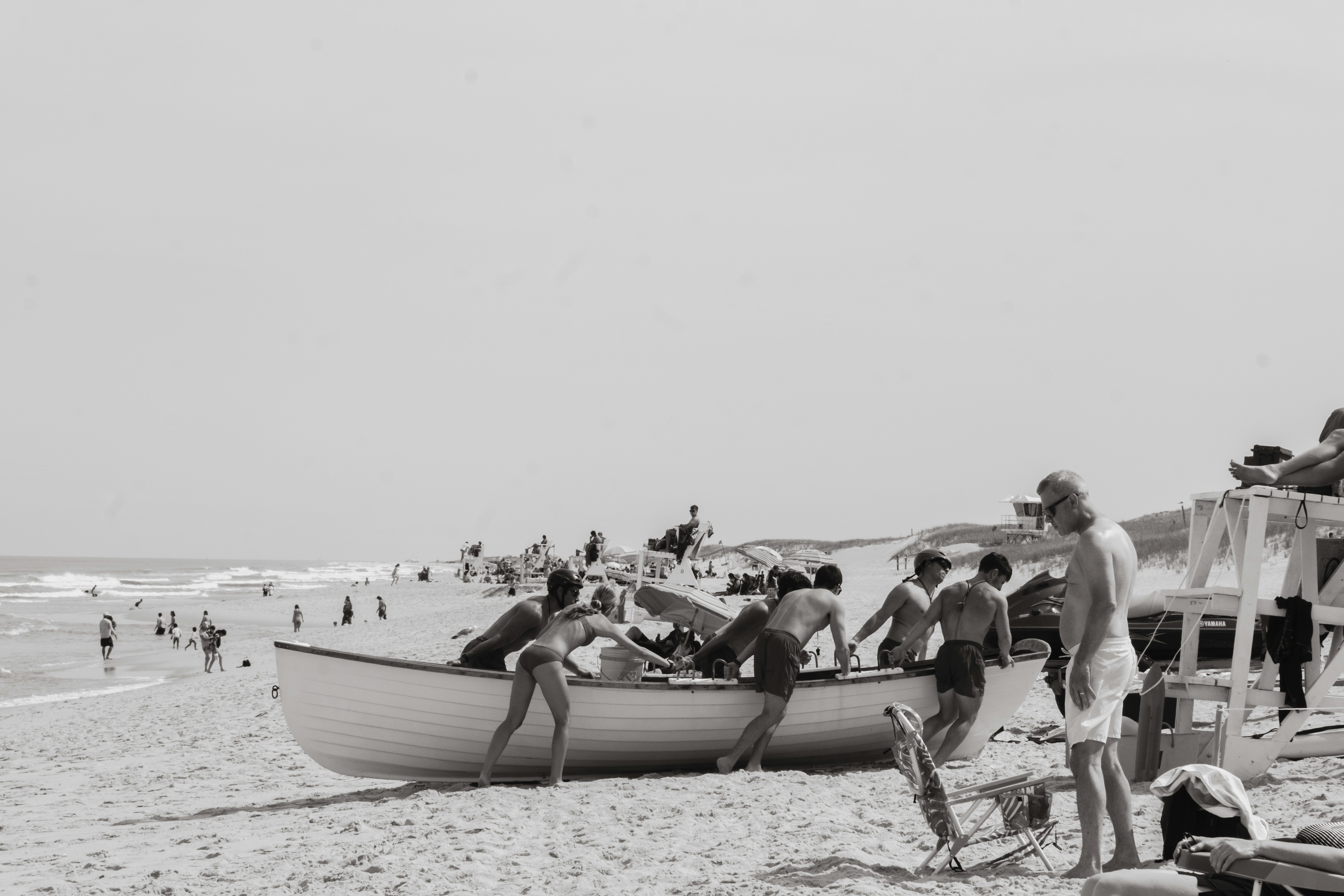 Waveside Liftoff: A Sunlit Beach Rescue in Black and White