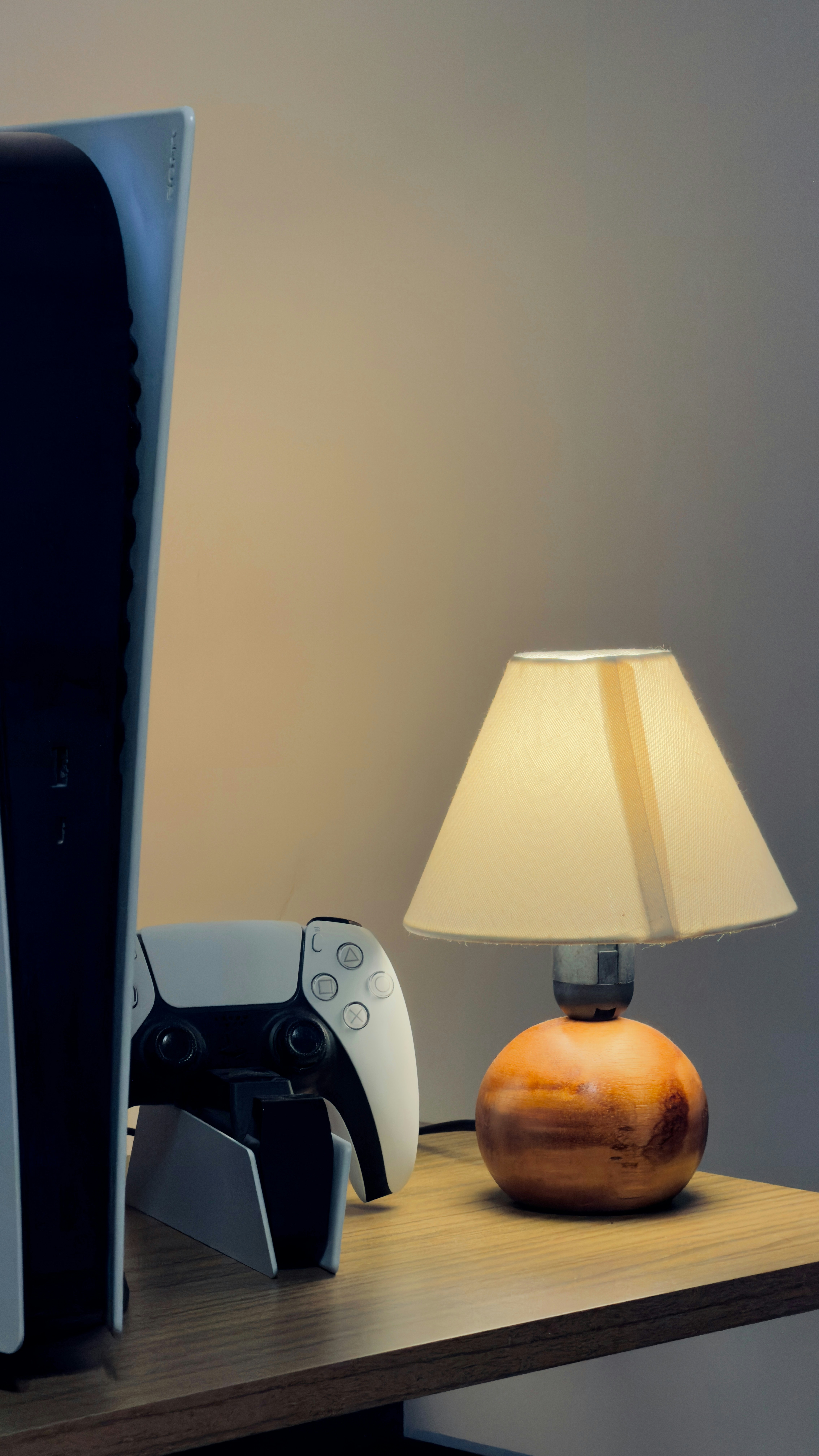Lamp and PlayStation 5 Controller on a Wooden Desk in Soft Office Lighting