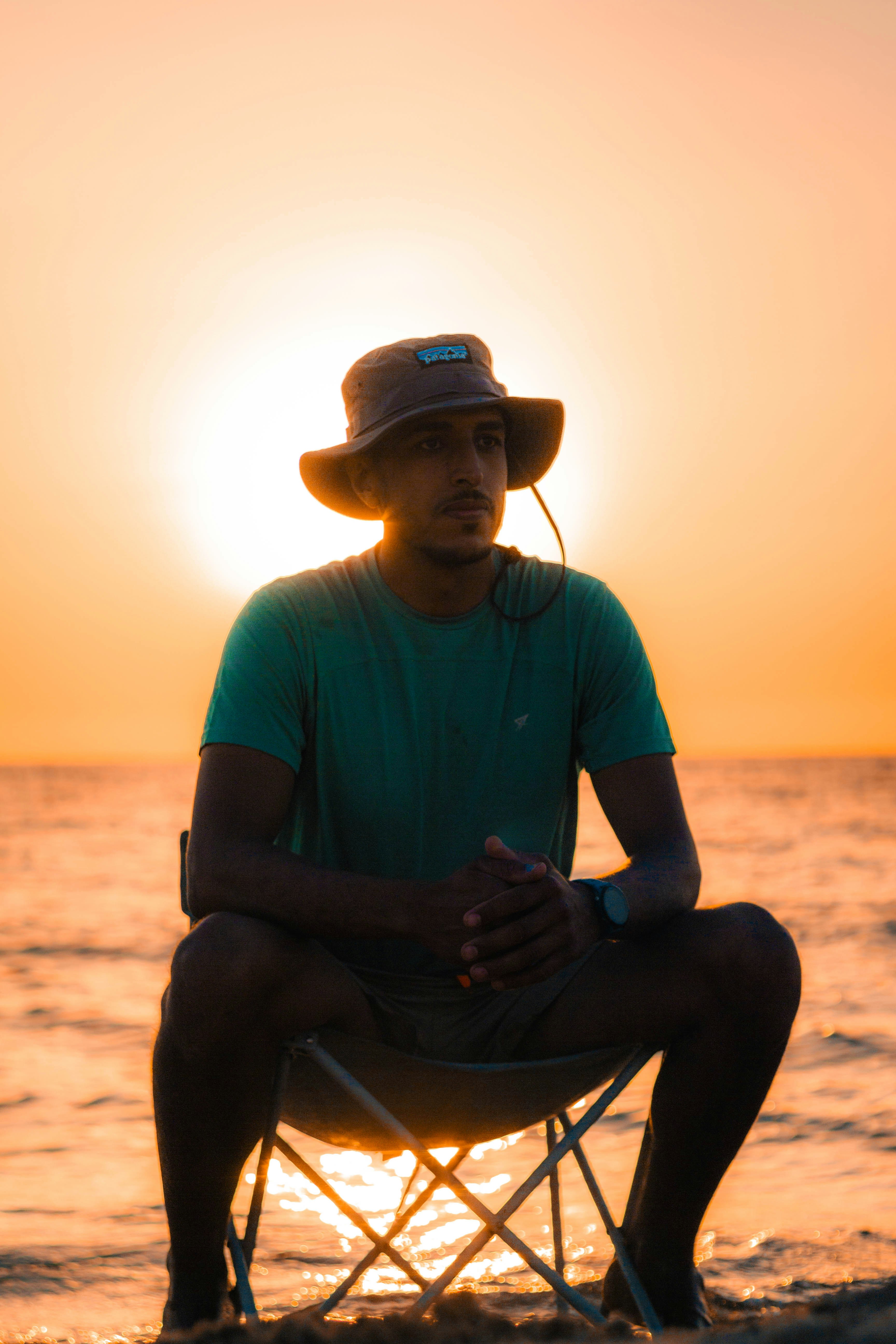 Silhouette at golden hour: a lone climber in a teal tee gazes into the horizon