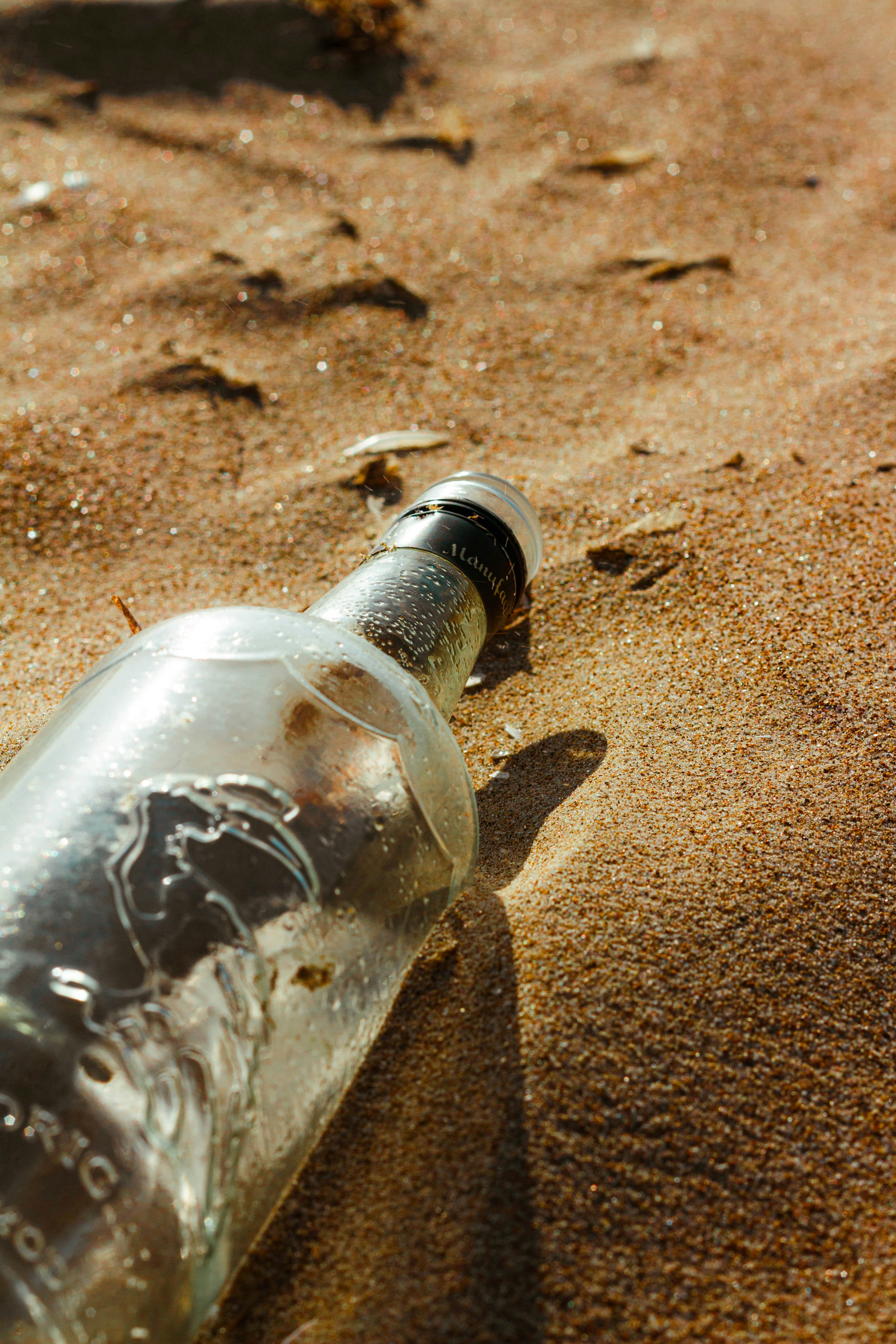 Deserted Bottle on Sunlit Sand: A Moment of Quiet Erosion