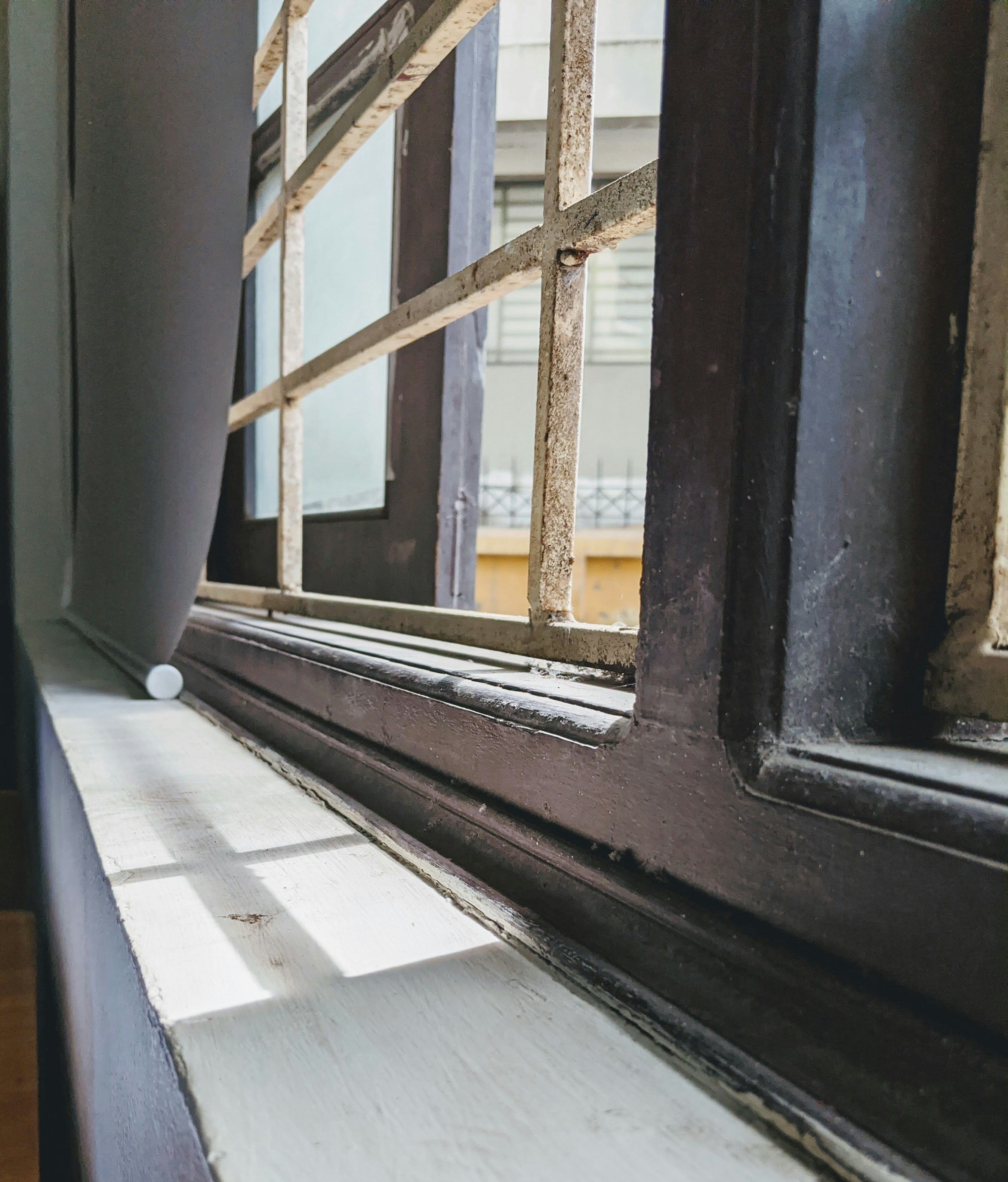 Sunlit Window Ledge: Rusted Bars and Shadowed Frame
