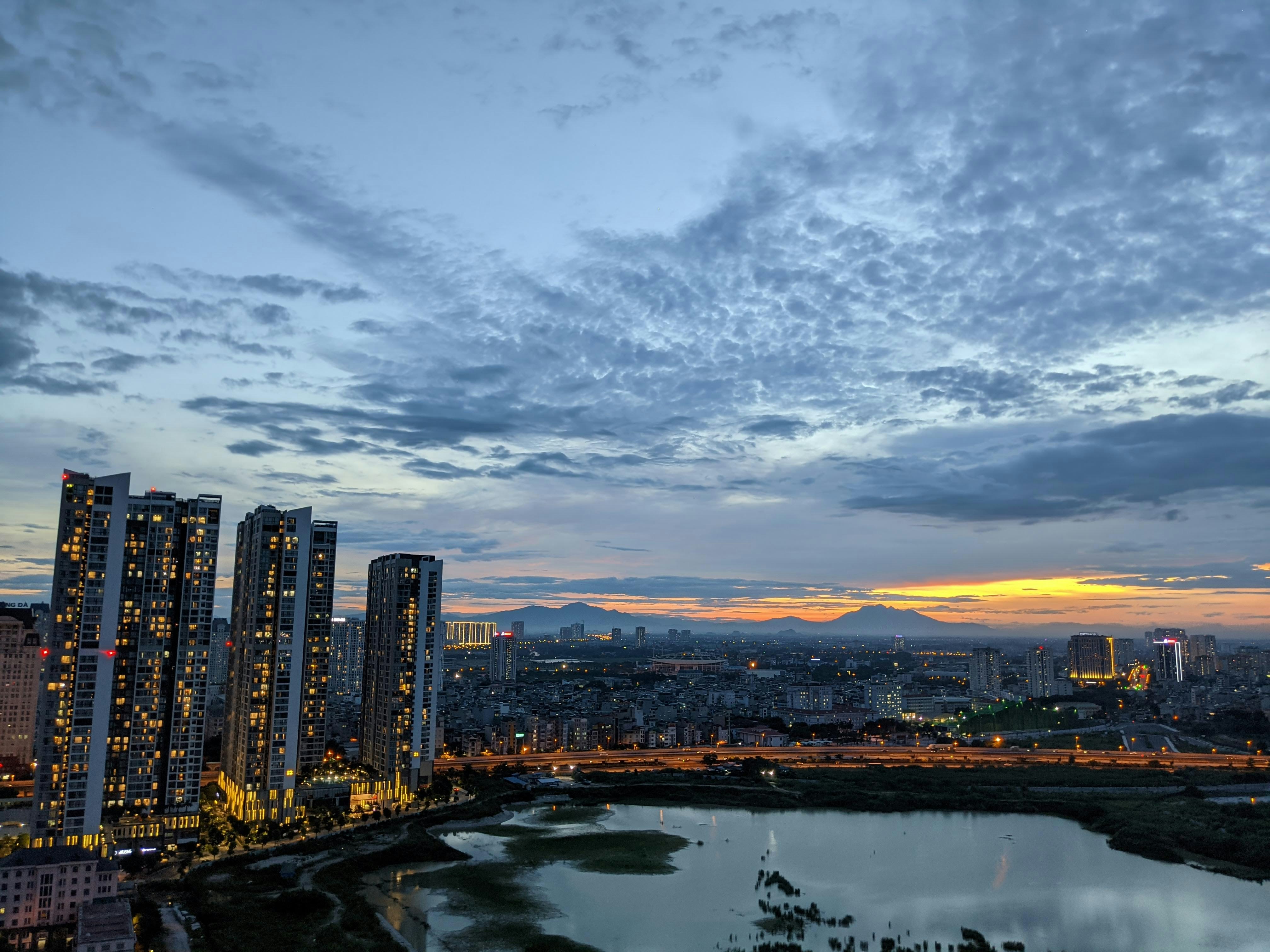 Dusk Over the Riverside City: Towers, Water, and a Golden Horizon