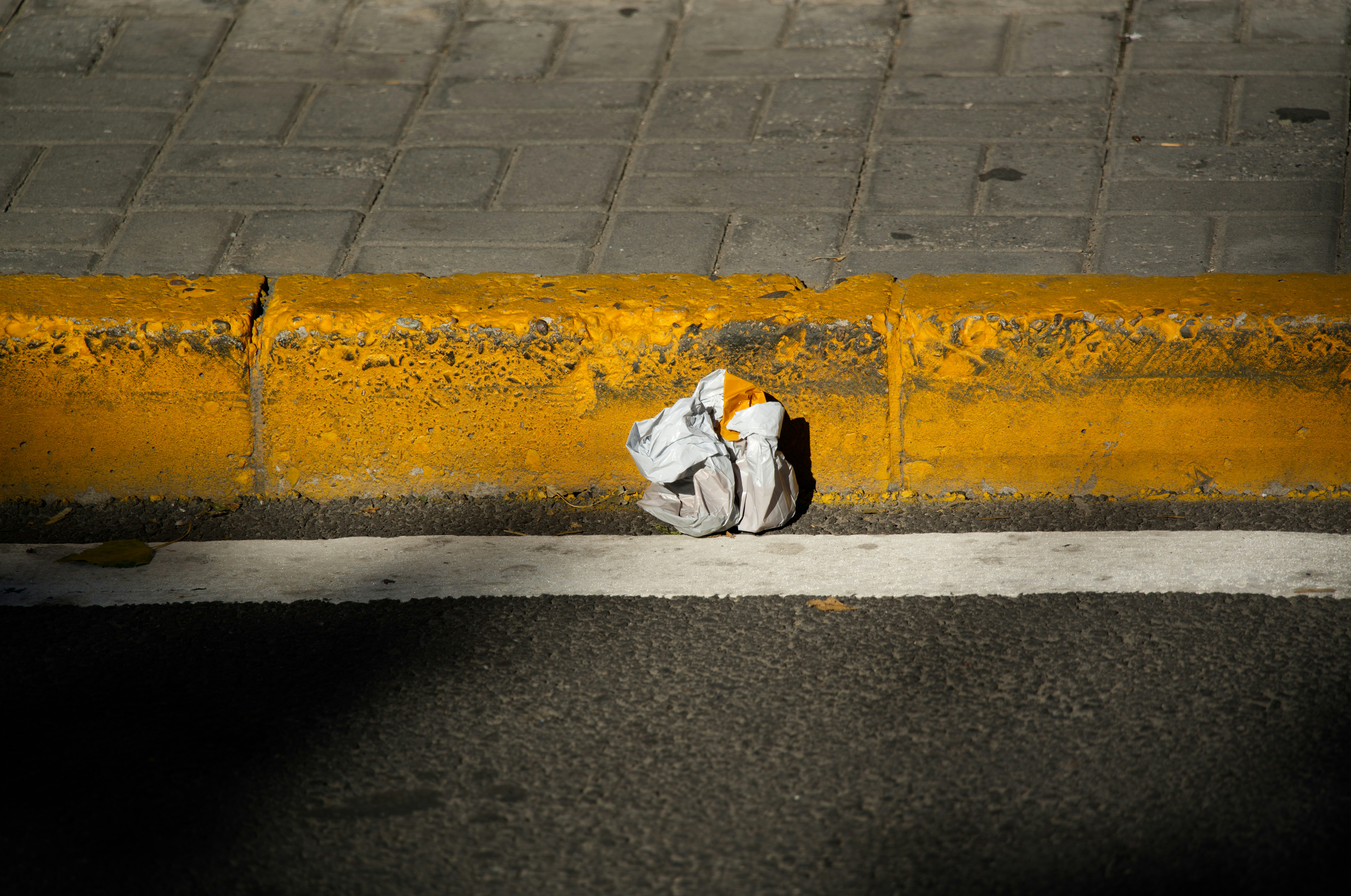 Crumpled white cloth resting on a yellow curb