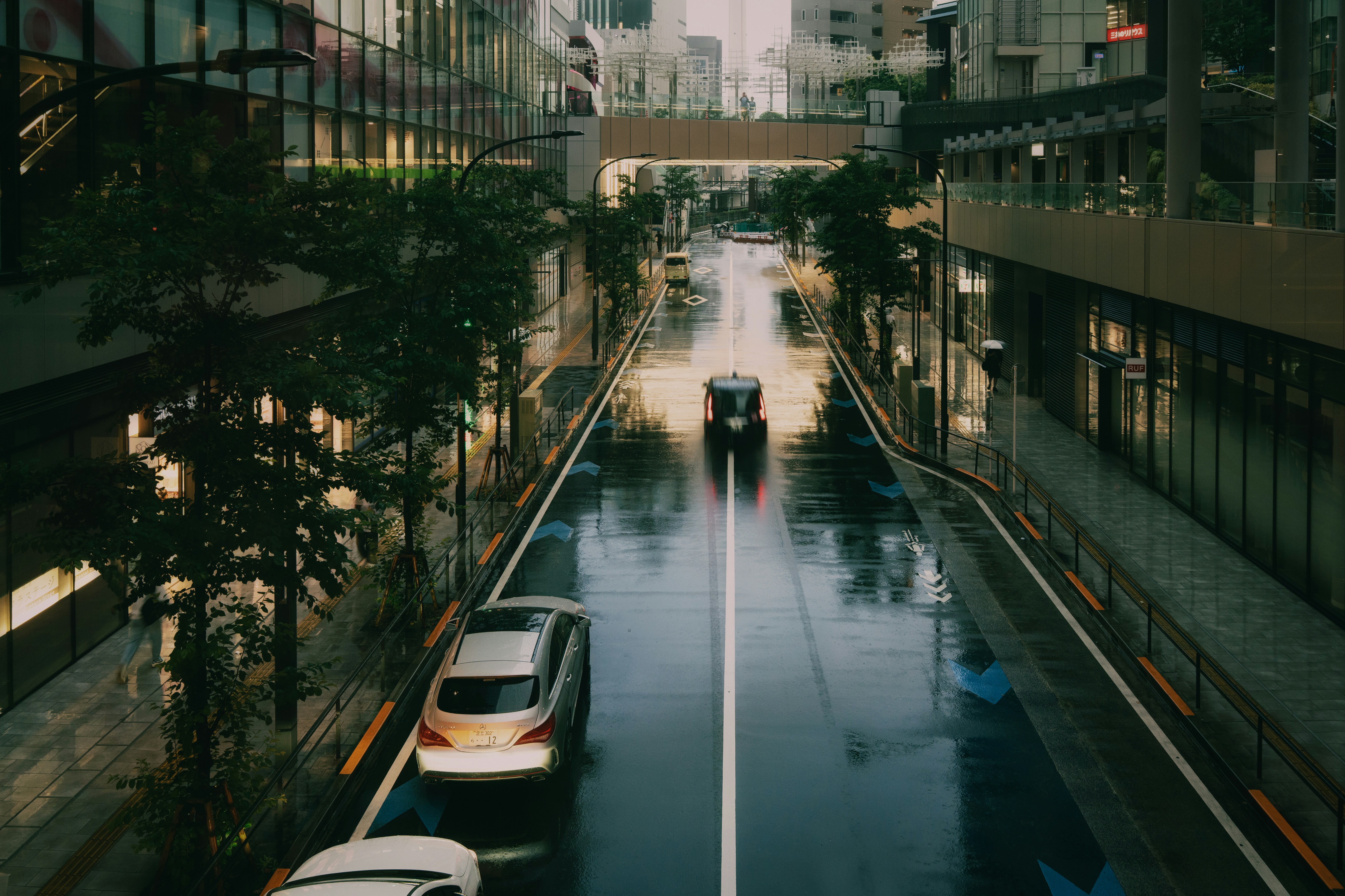 Wet city street with cars and modern buildings.