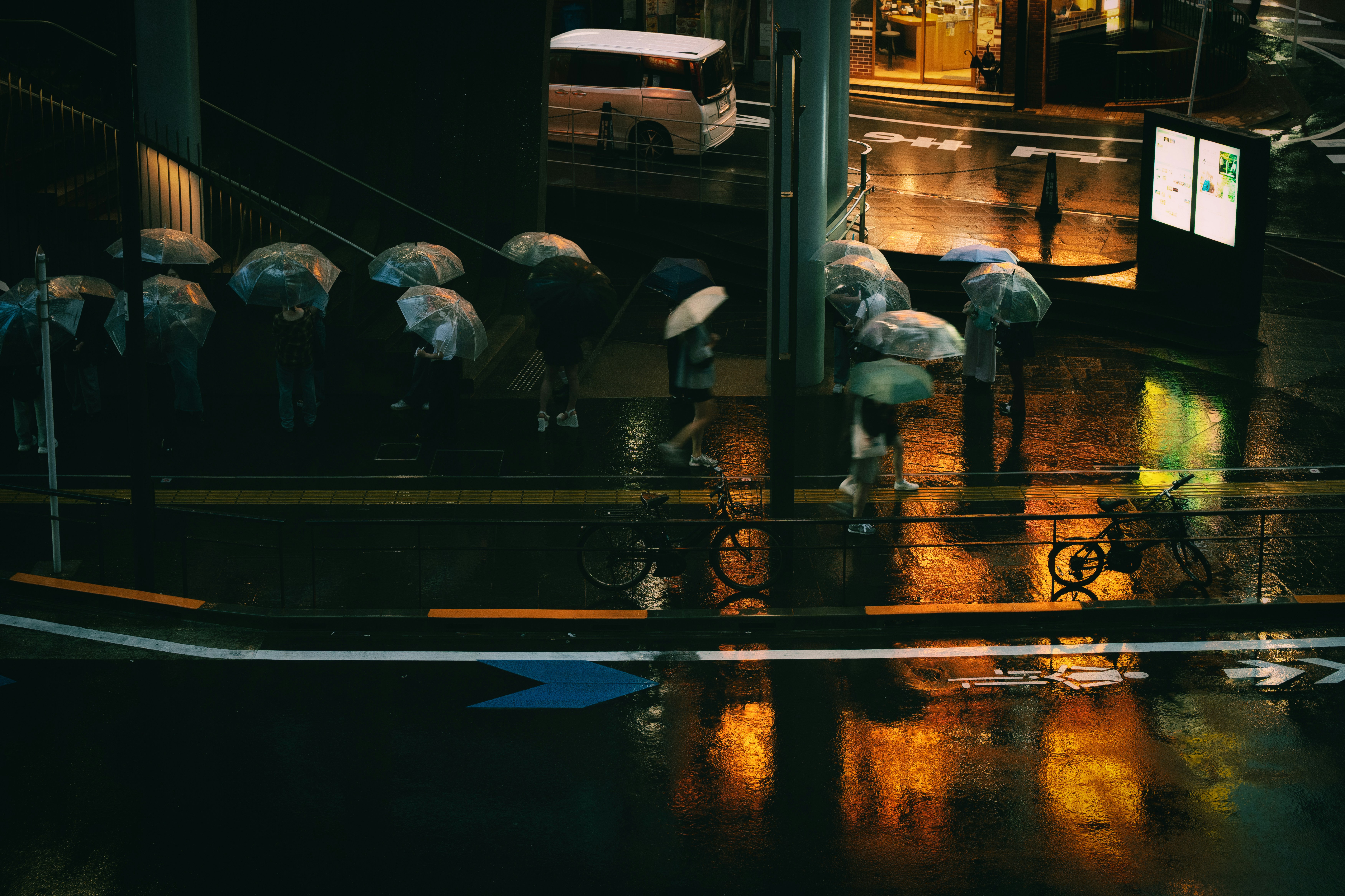 Rainy Crosswalk Glow: Umbrellas and Neon Reflections