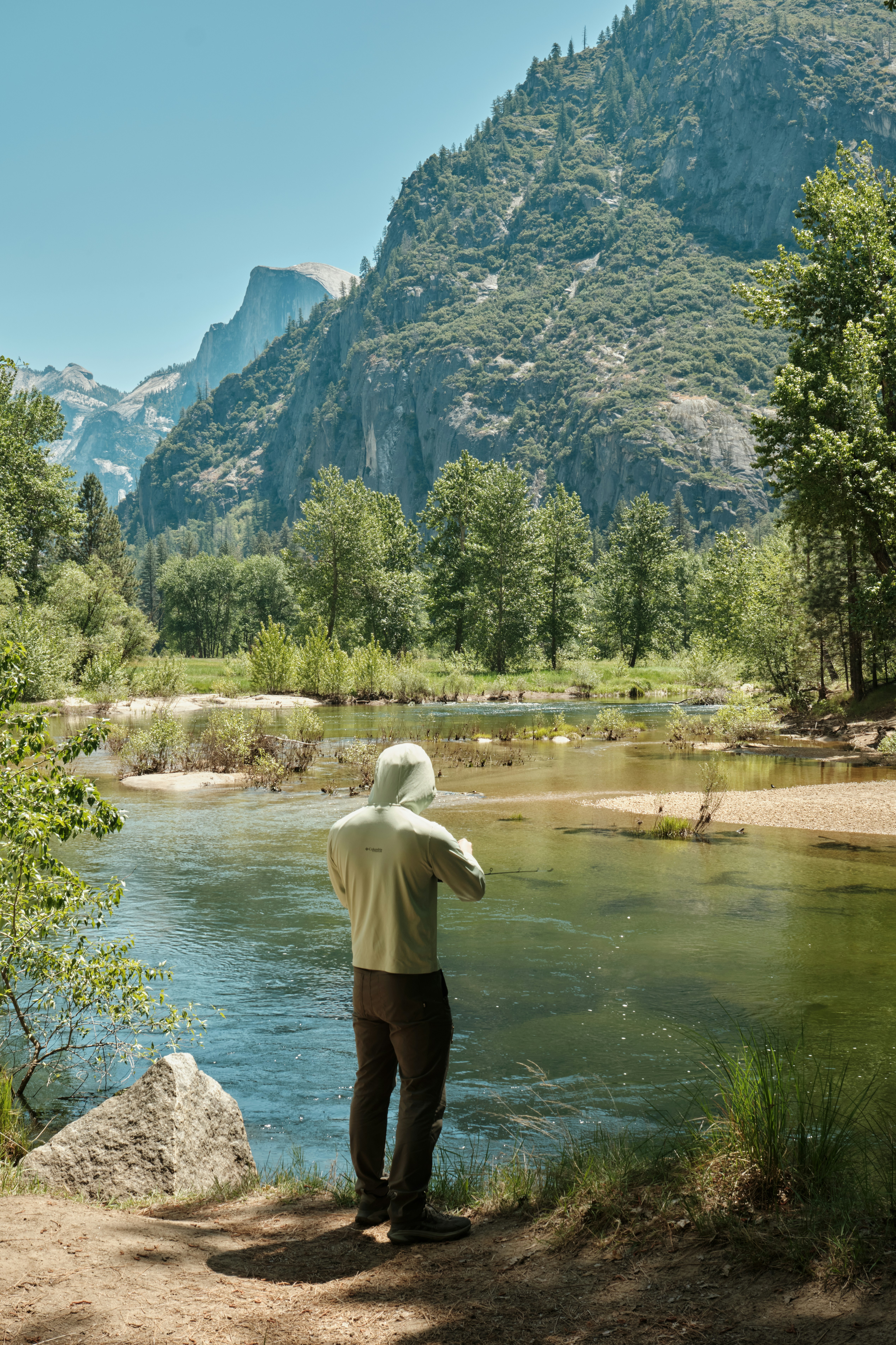 Hiker in a Quiet Valley by the River under Alpine Cliffs