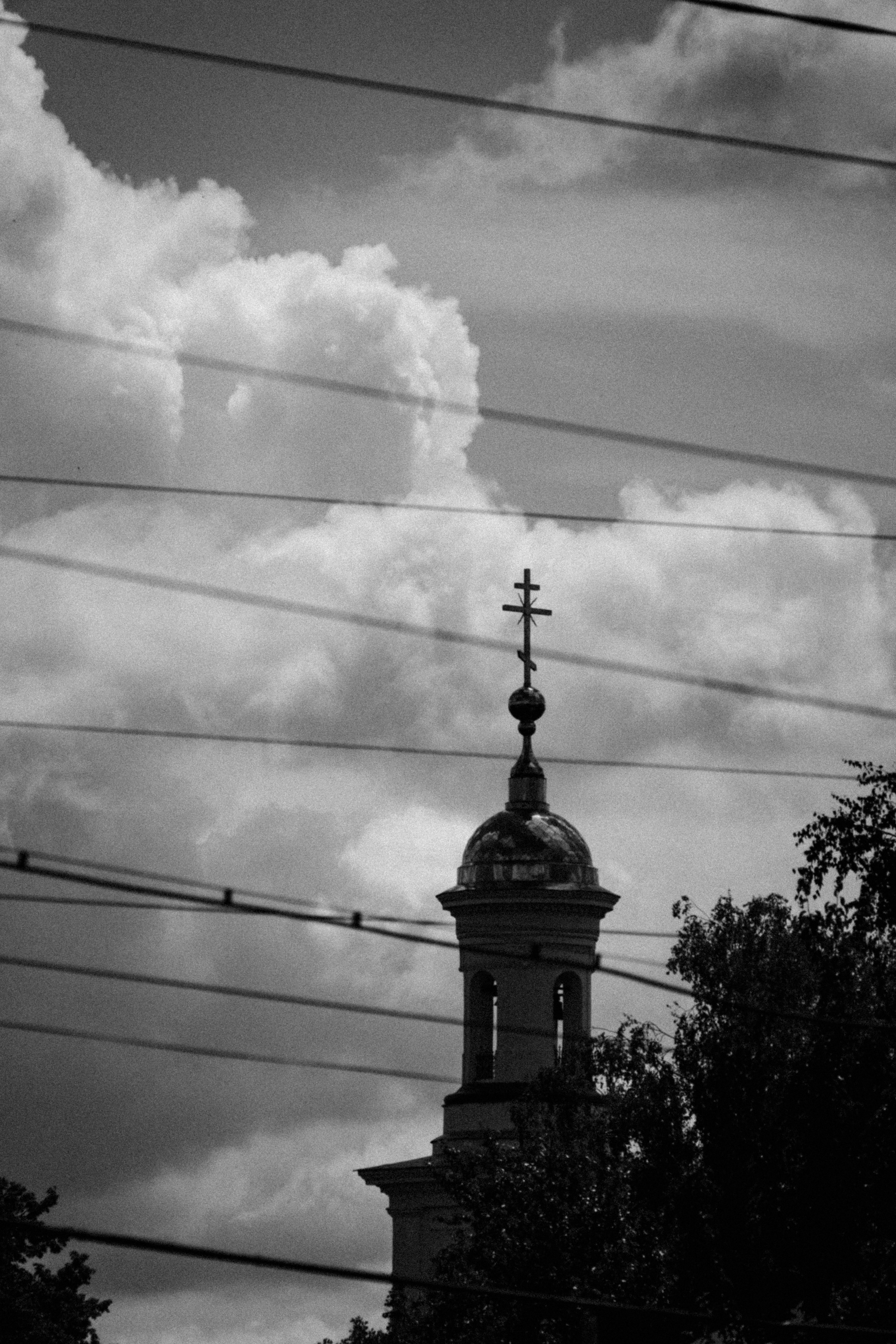 Cross atop the church tower piercing the clouds