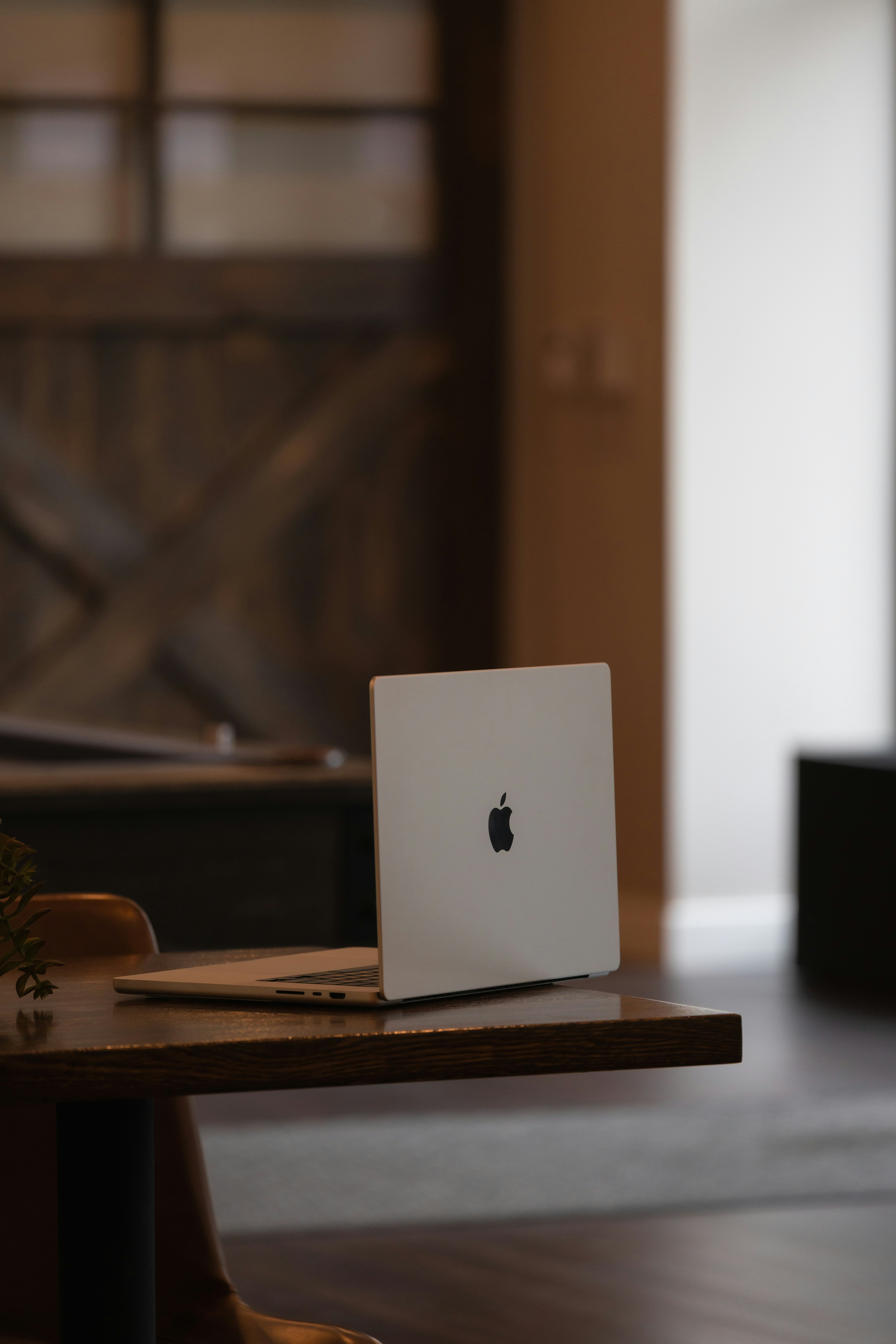 Silent Focus: A Silver MacBook Upon a Wooden Table in a Dim Studio