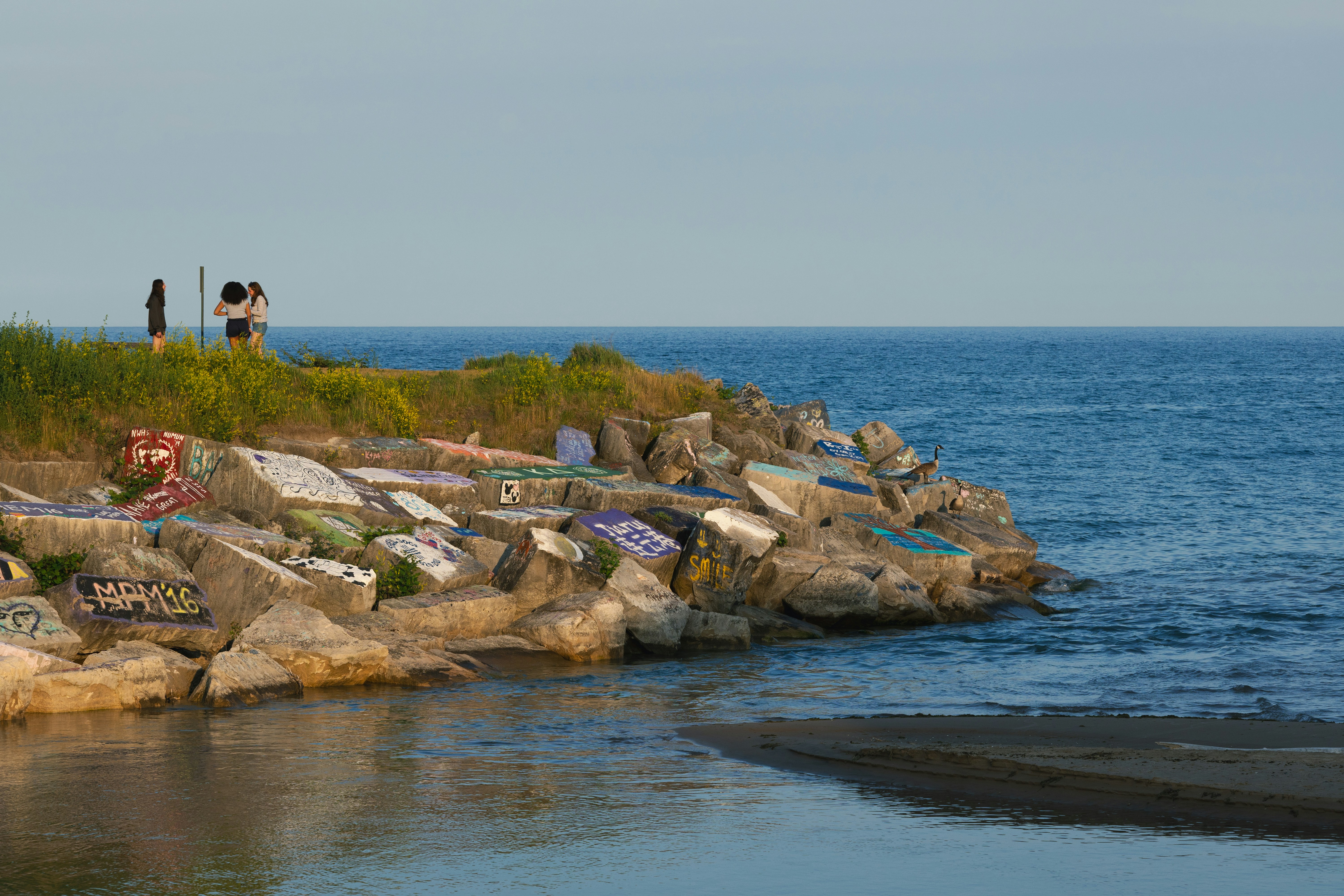 Ledge of Graffitied Breakwater Beneath an Open Sea