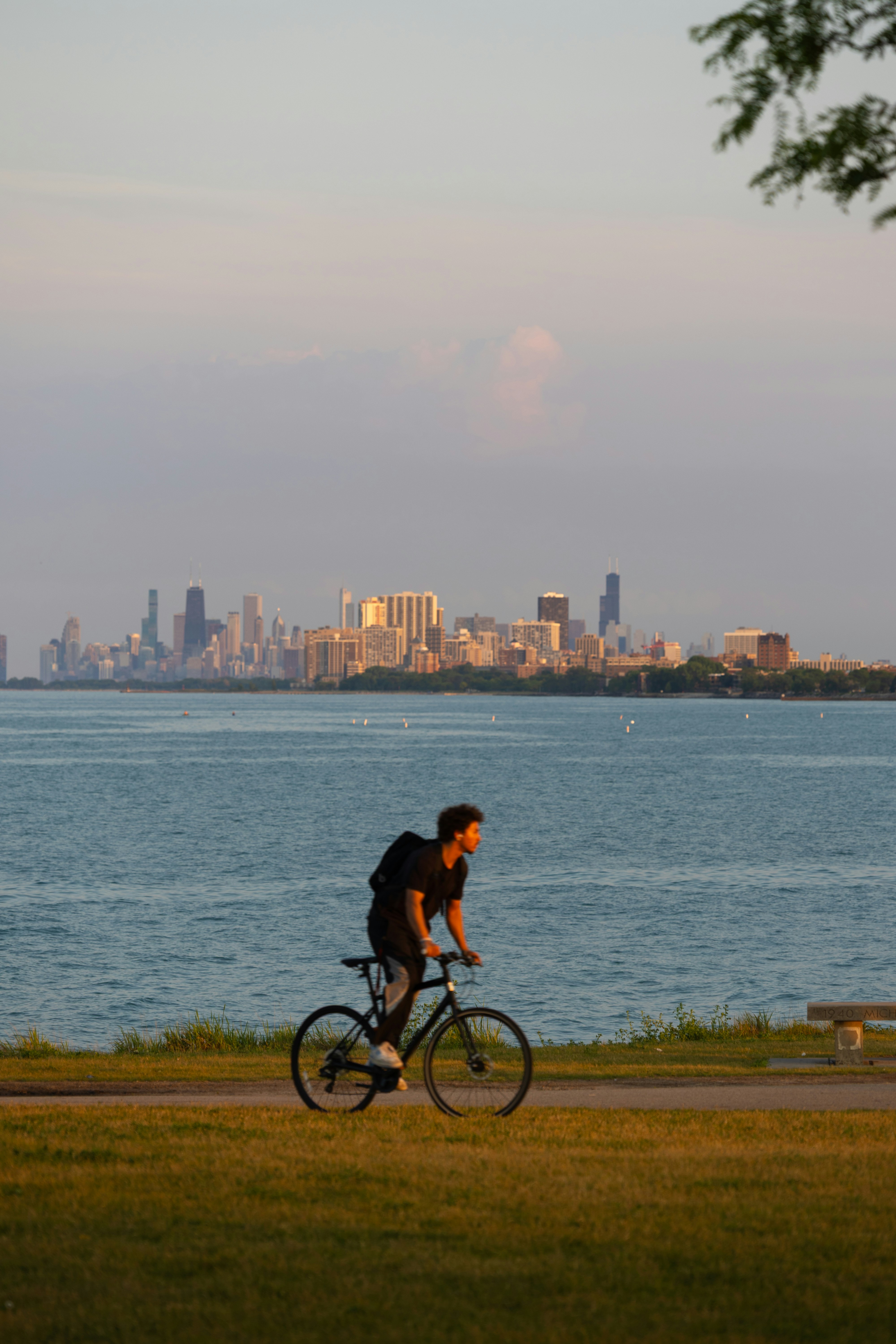 Riverside Rider: A lone cyclist journeys along the shore with the city skyline at dusk