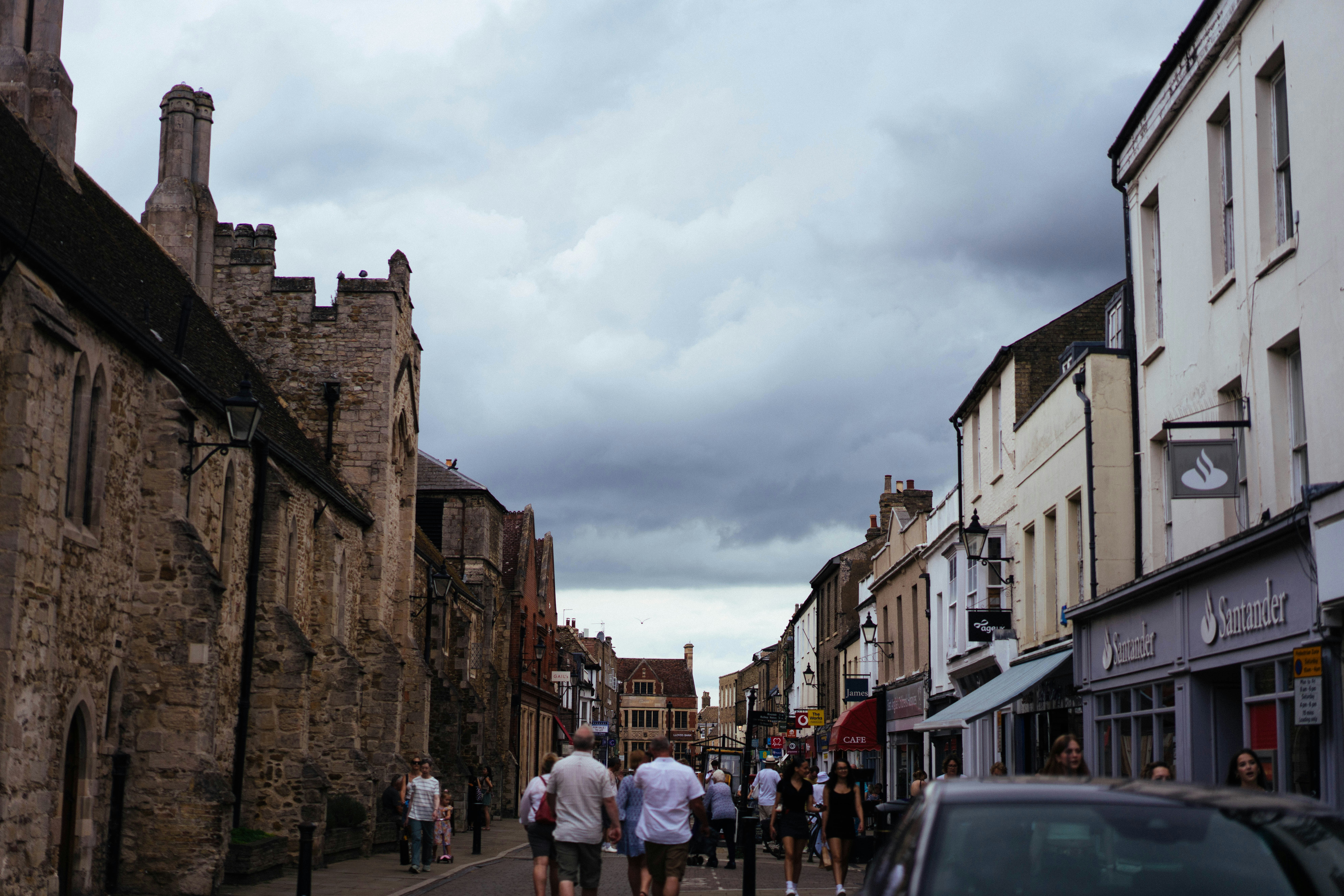 Town Street in Focus: People Amble Under Cloudy Skies