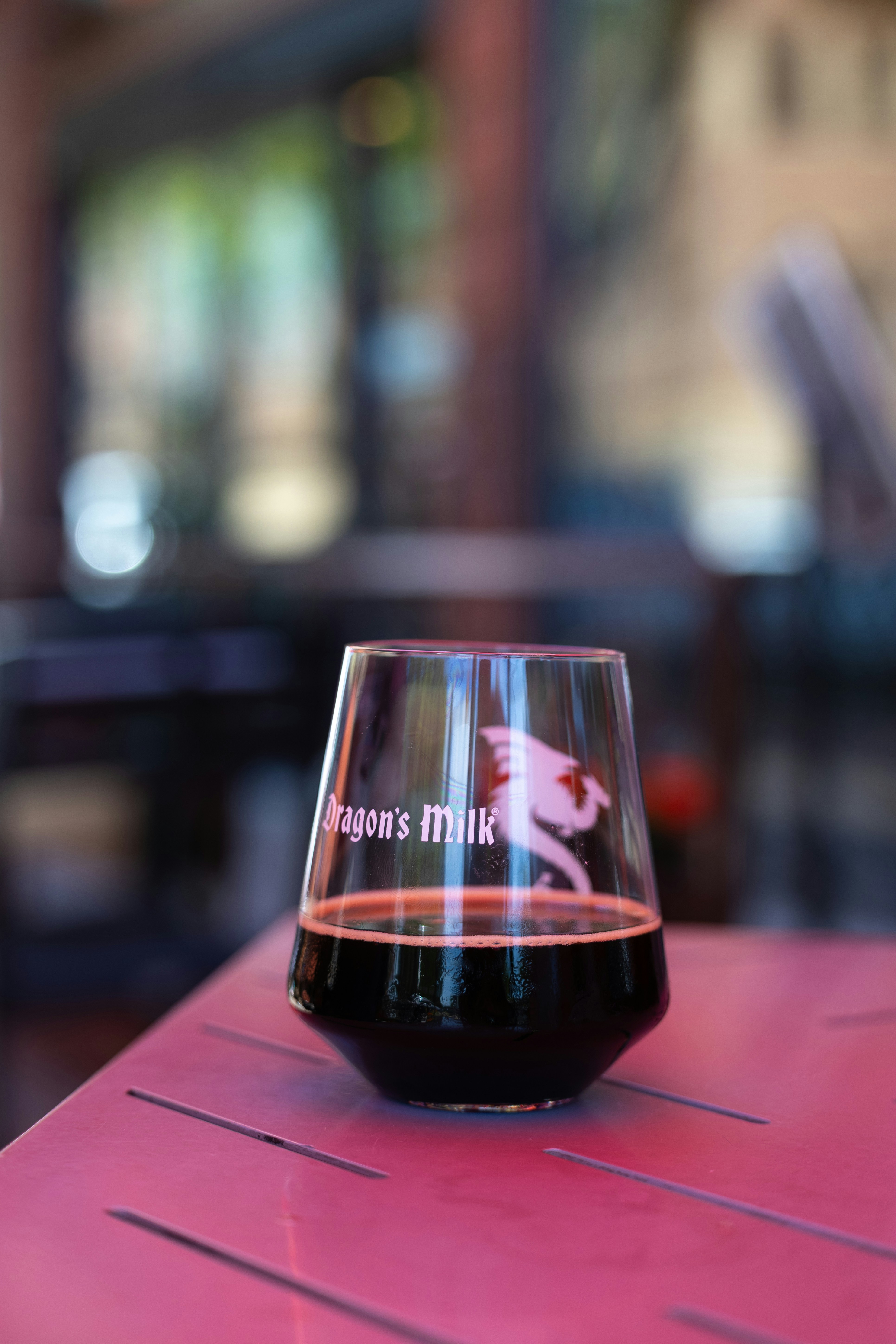 Wine Glass in Focus: Dragon’s Milk Distilled on a Red Table