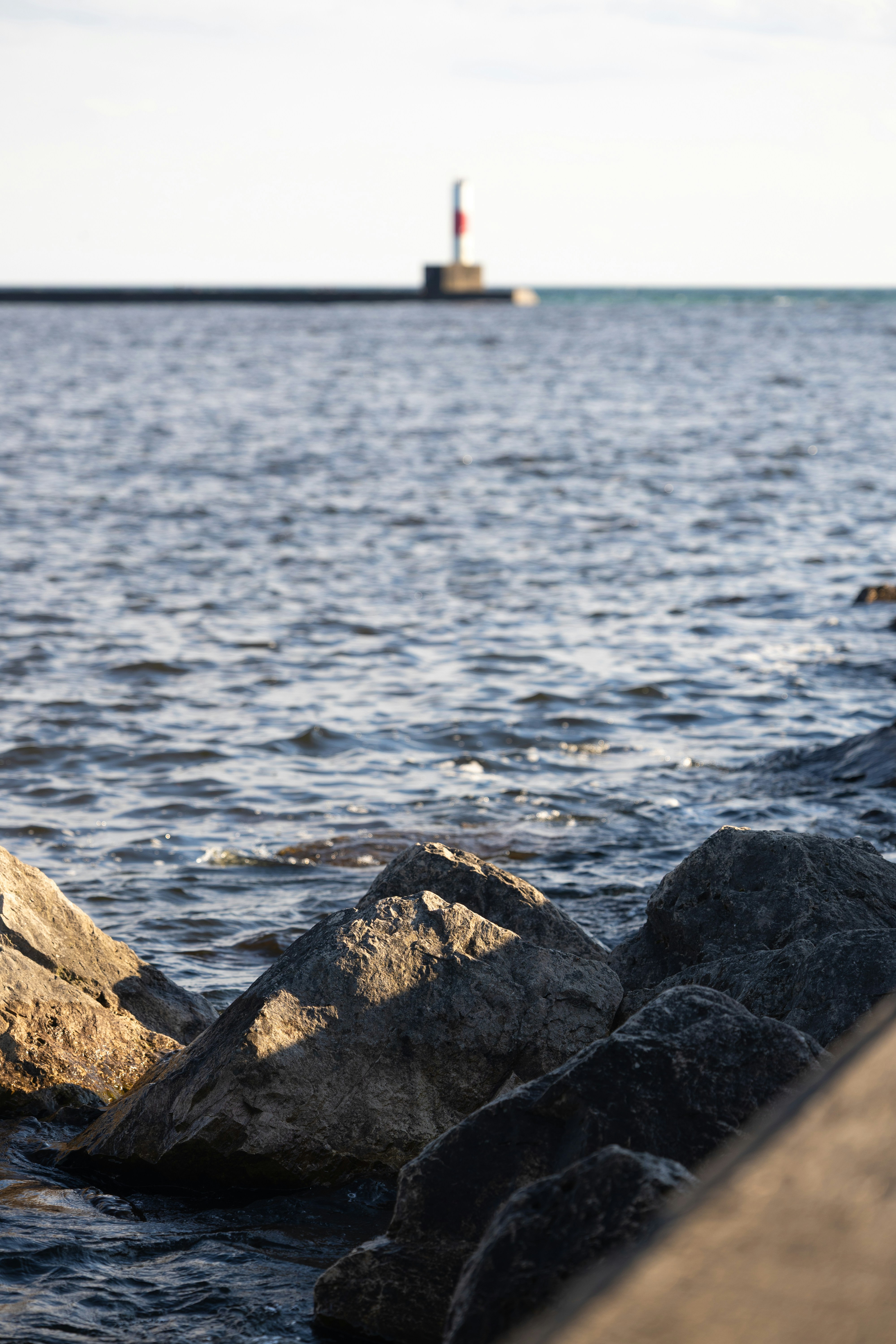 Lighthouse Milestone: Calm Sea, Weathered Rocks