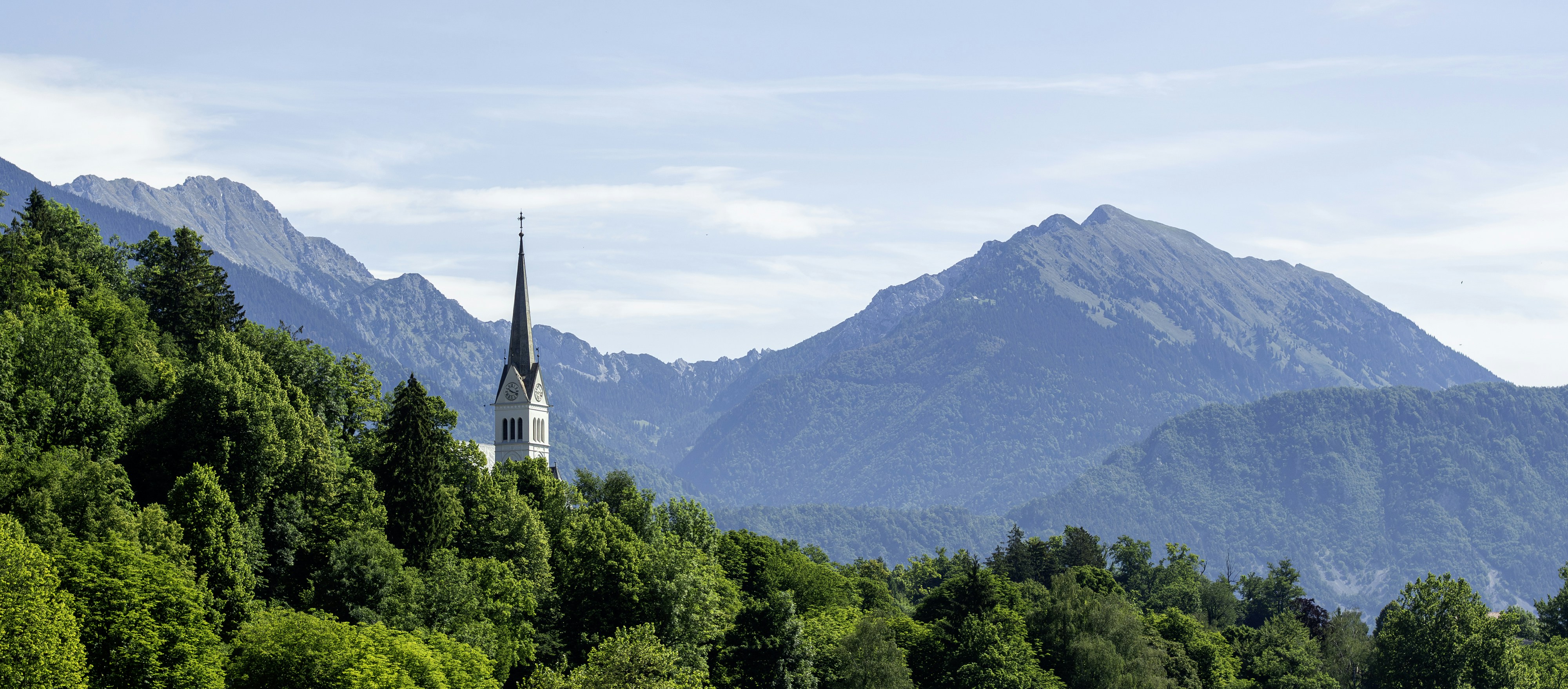 Spire Amid the Alps: A Chapel Needle Rising from Verdant Hills