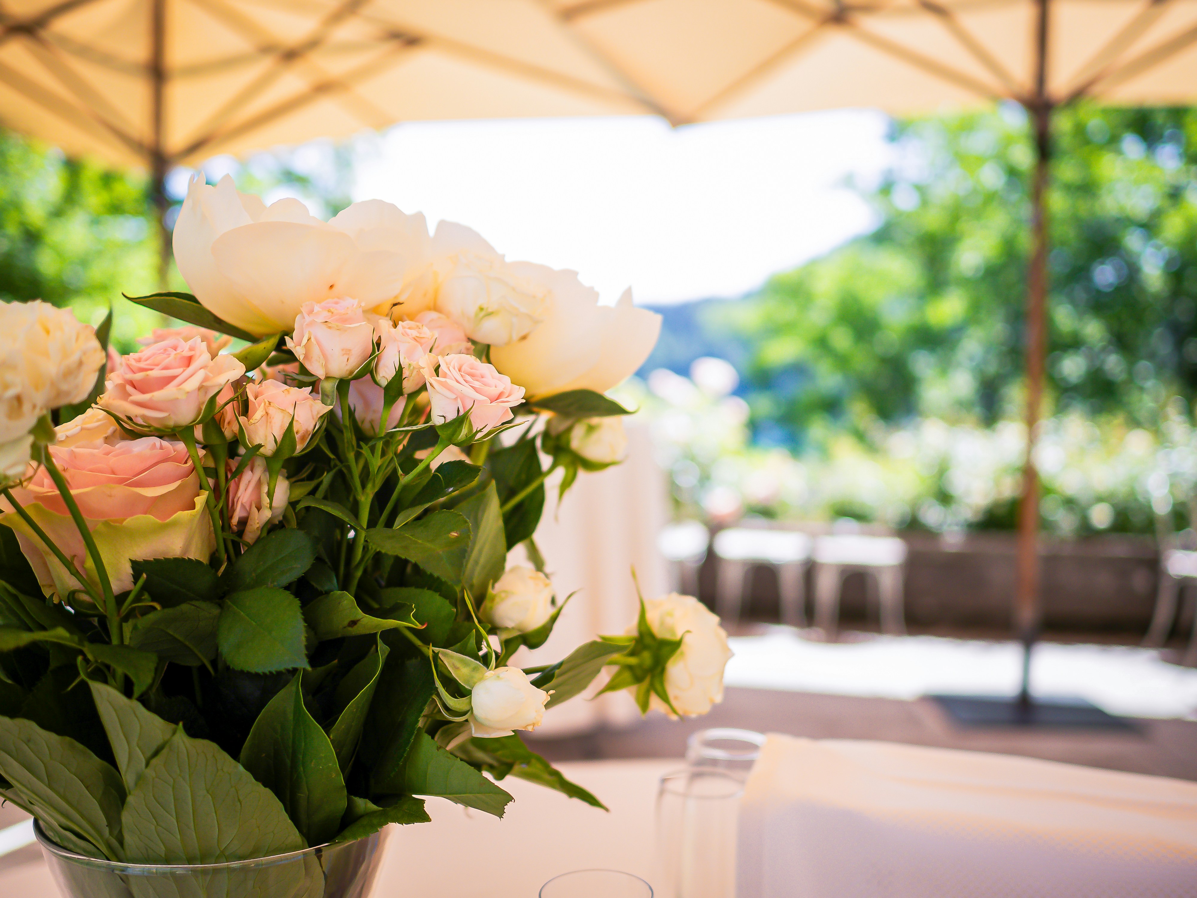 A bouquet of pink and white roses on a romantic wedding-style table setting at Bled Island, Slovenia. A delicate floral arrangement surrounded by the timeless beauty of this iconic location.