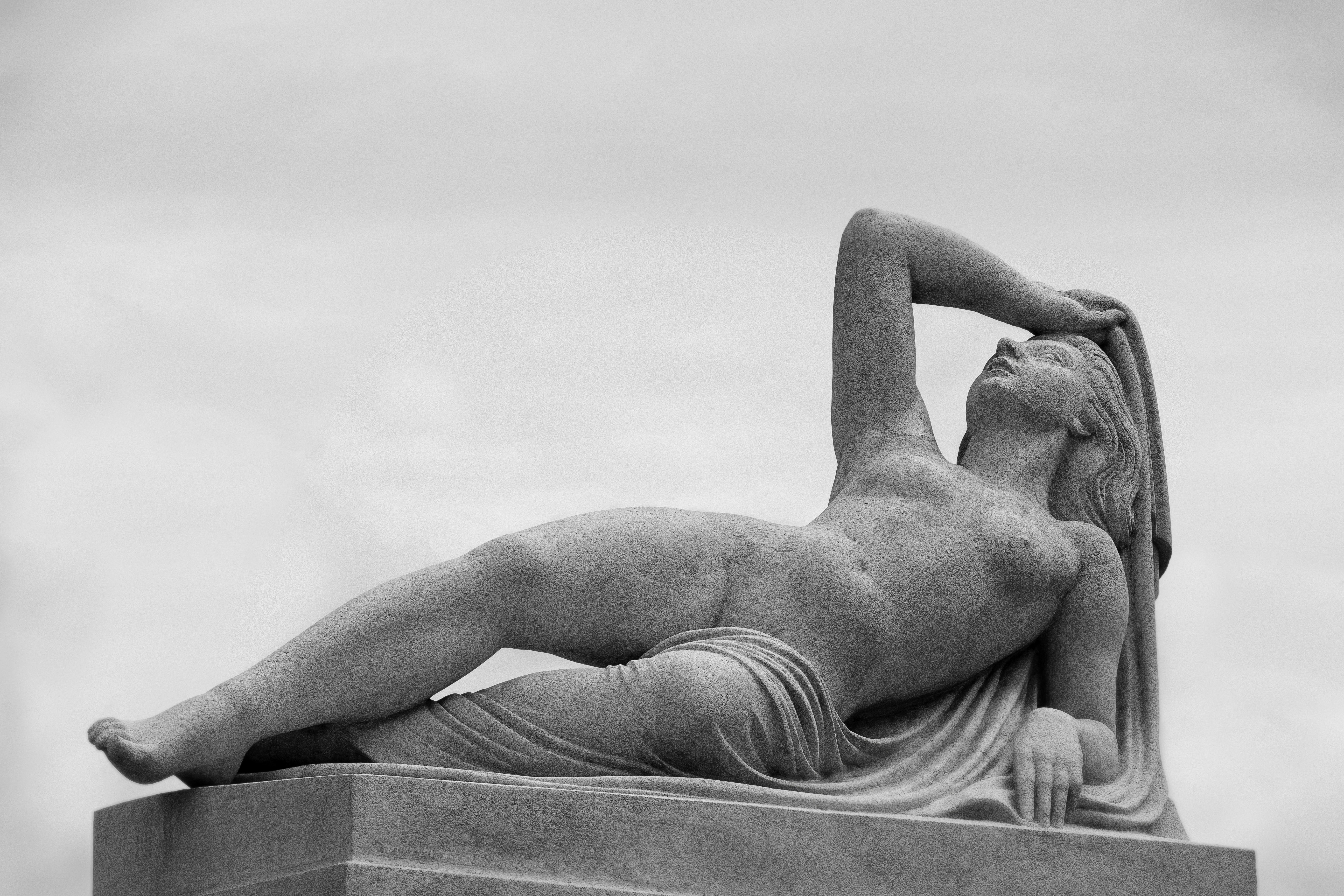 Lying Muse: A Reclined Statue Against a Clouded Sky