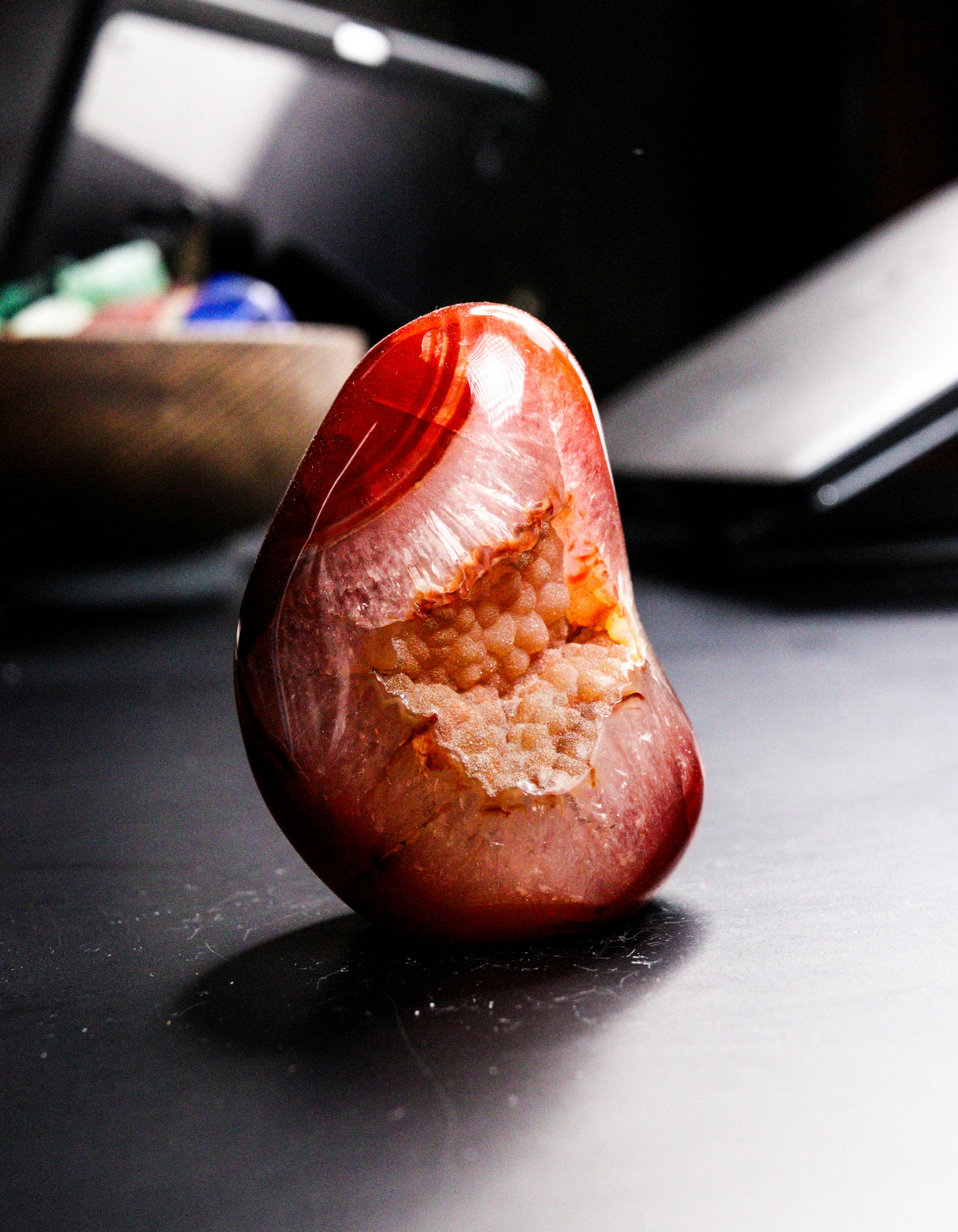 Juice of the Stone: a close-up of a hollowed red fruit on a dark desk