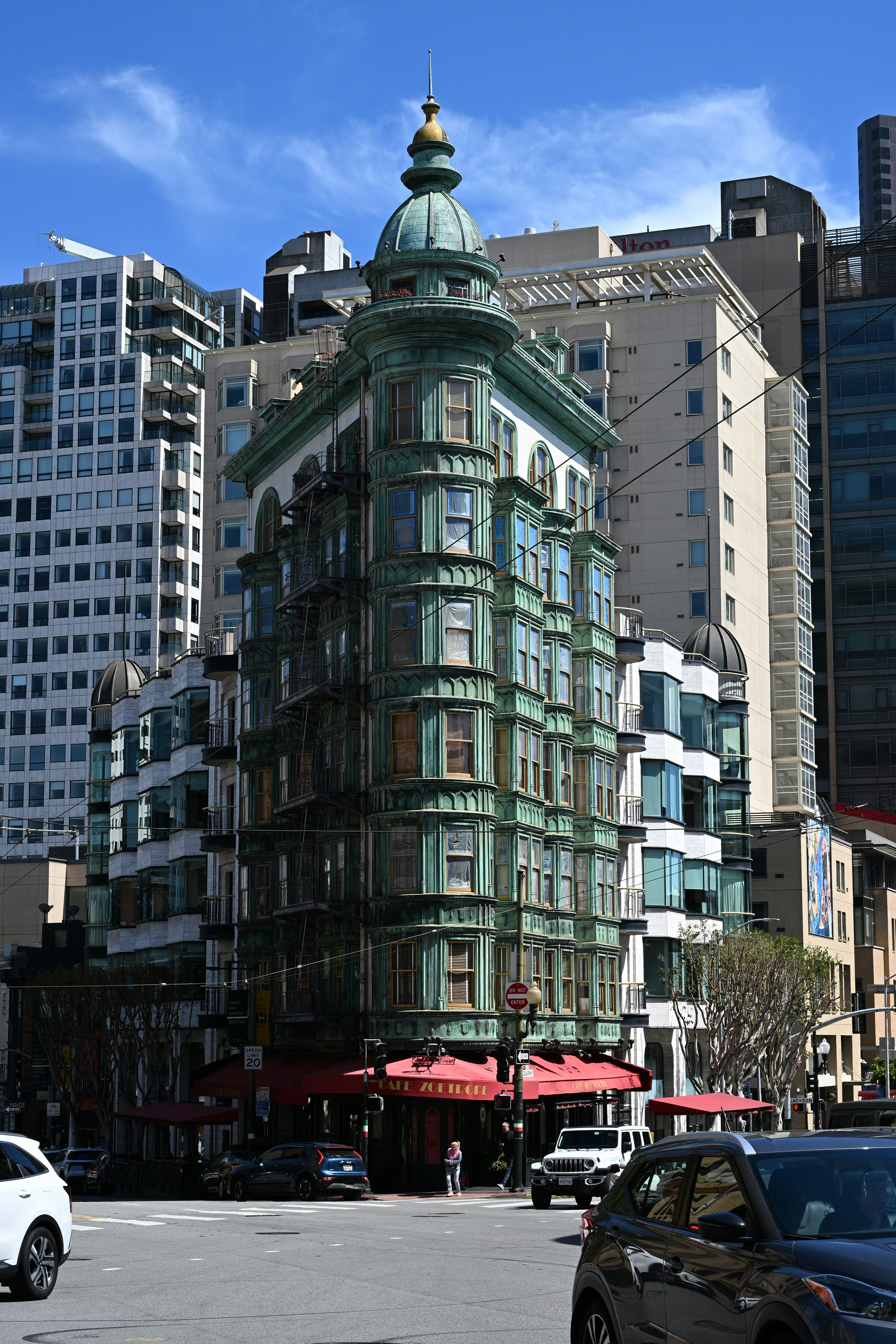 Green vintage tower amidst glass giants in a sunlit city block
