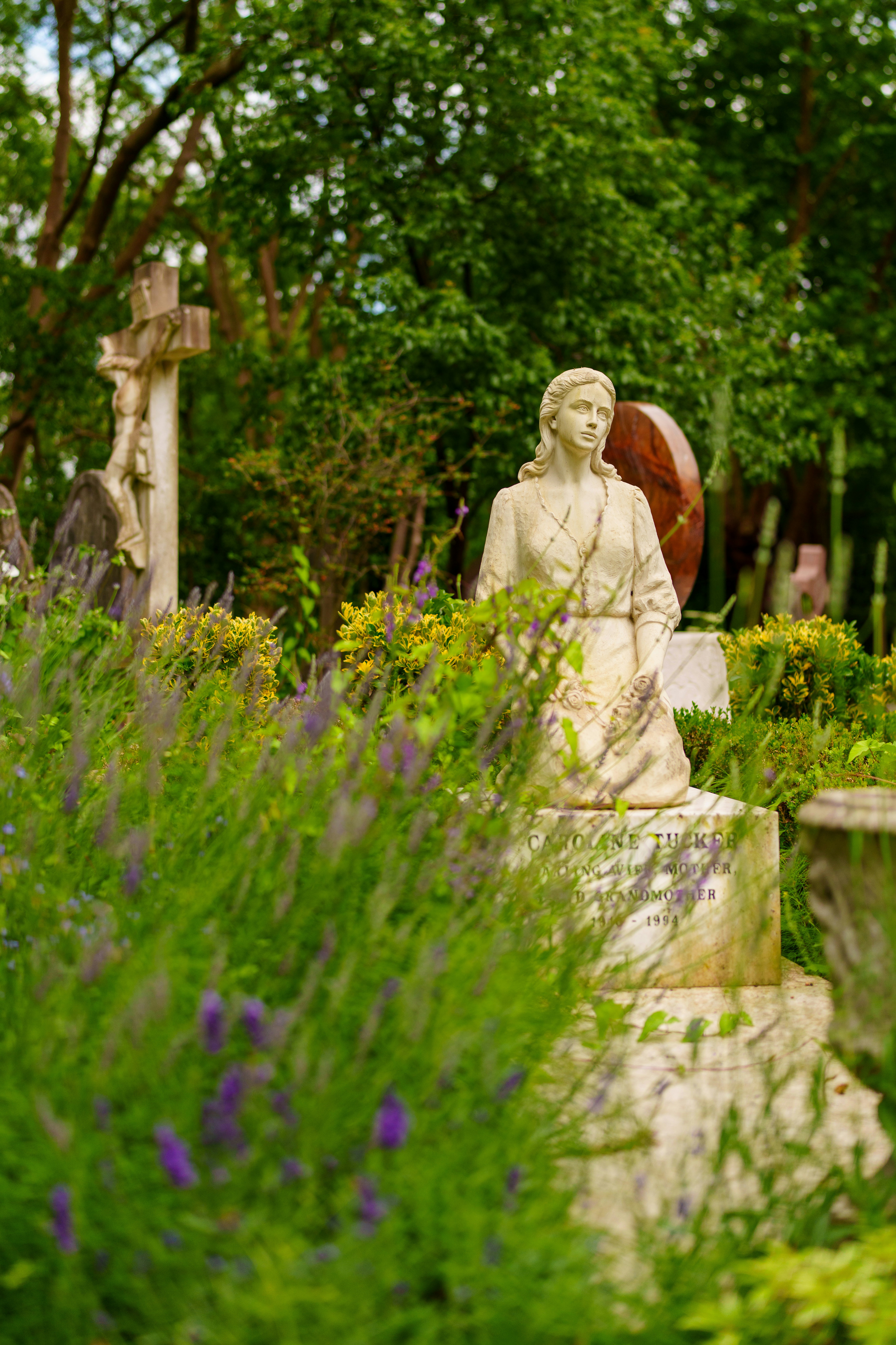 Carved stone figure of a woman on a Victorian grave, seen through a soft foreground of lavender