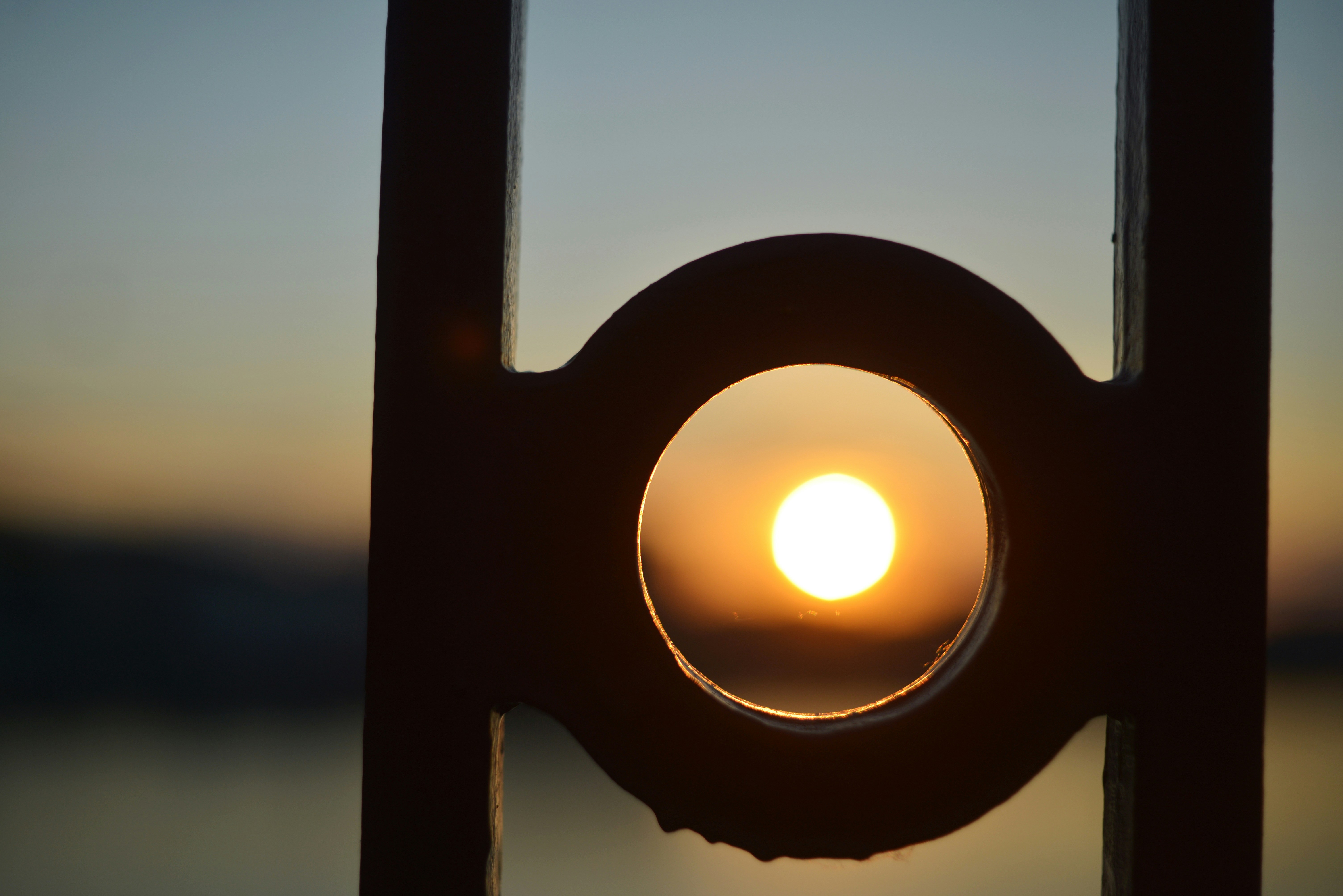 Sunset through a circular hole: a metal frame frames the flame
