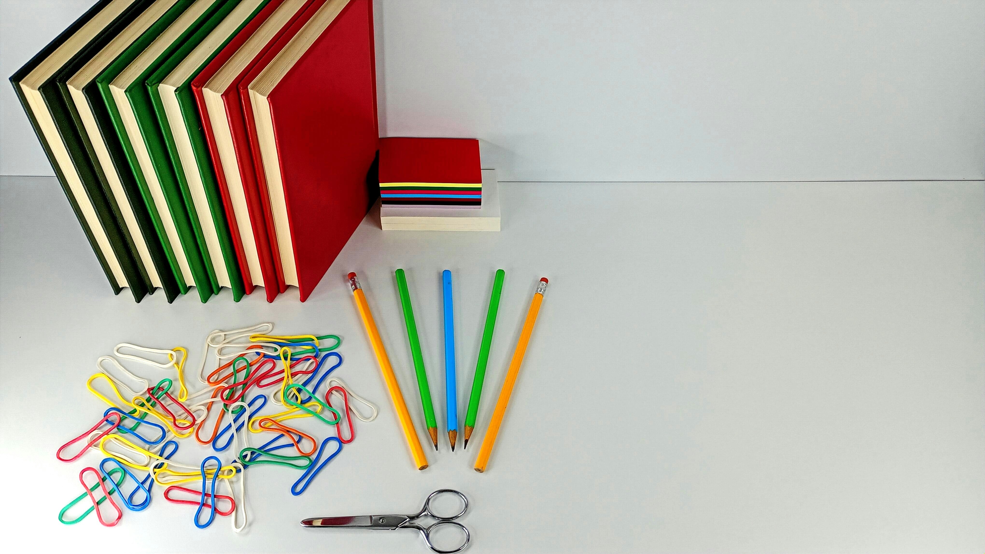 Colorful school supplies including books, pencils, paper clips, sticky notes and scissors neatly arranged on a white background with ample copy space. Education, learning, organization, study and back to school concept.