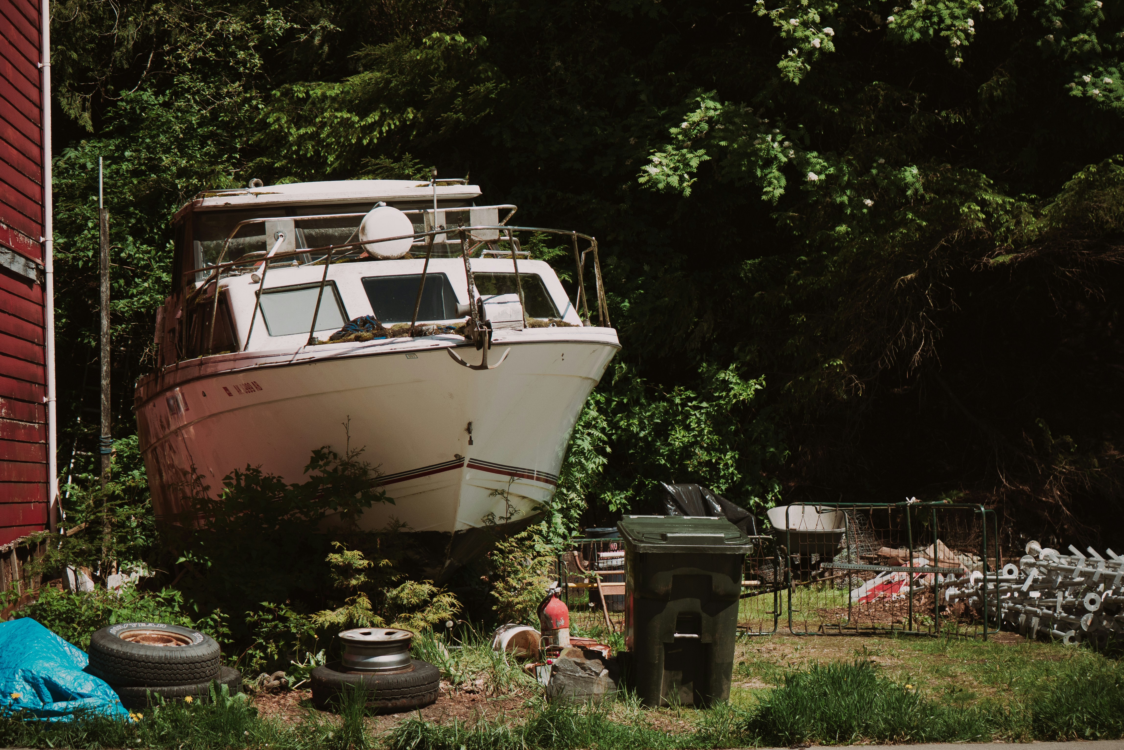 Abandoned Harbor Keepsake: Boat Resting Among Weeds and Debris