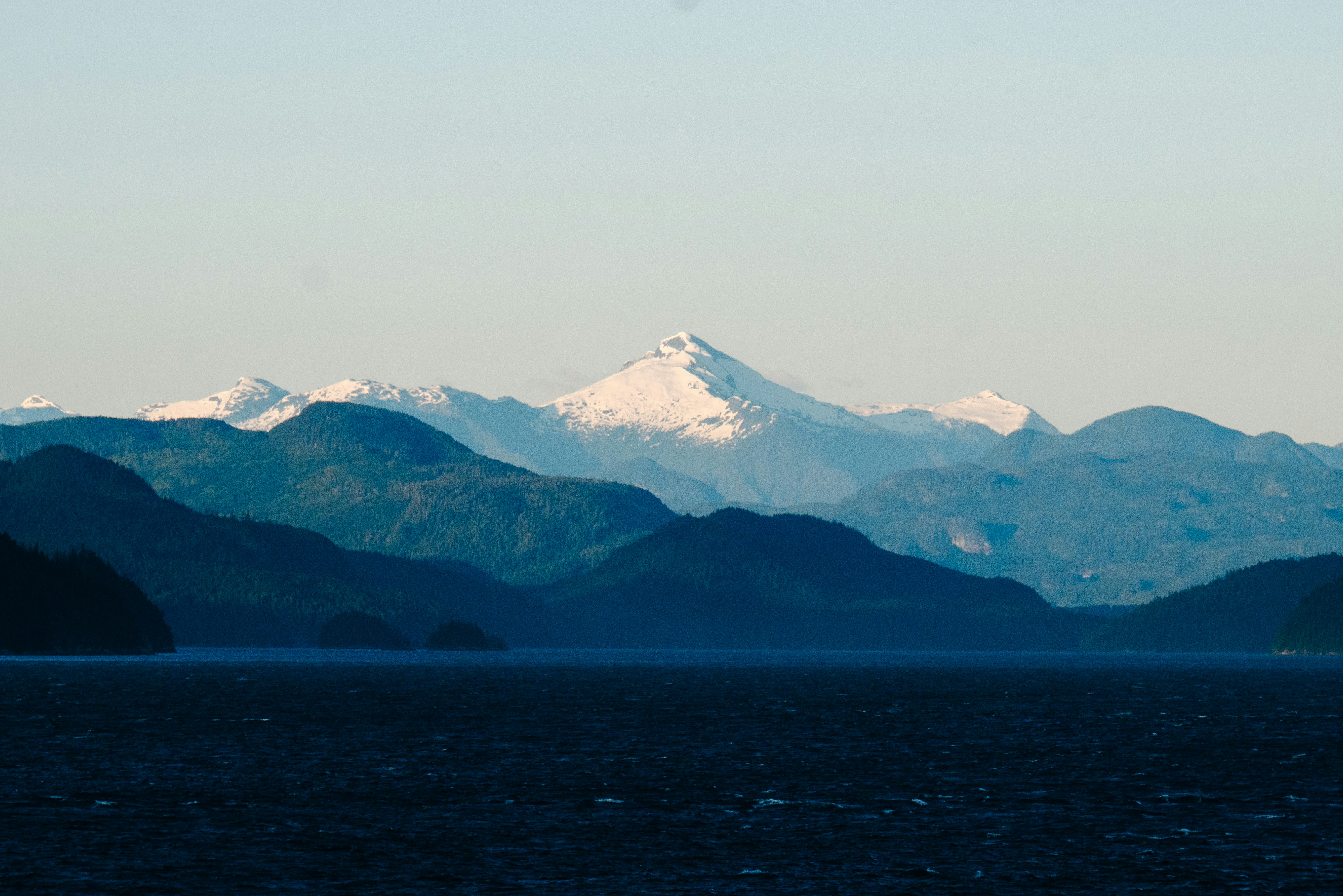 Snow-capped peaks rising over a quiet sea horizon