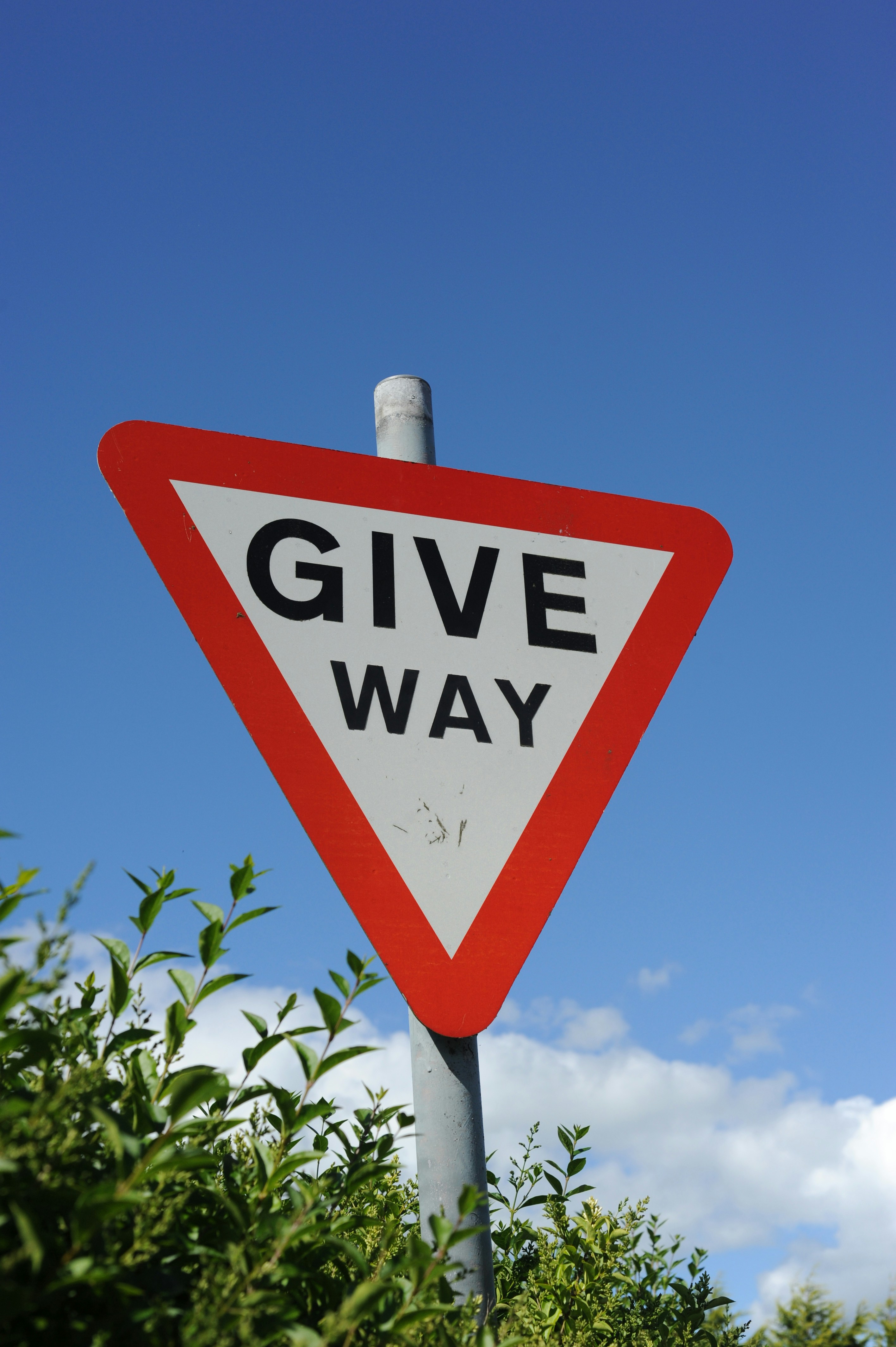 Give Way Sign Soaring Against a Clear Blue Sky