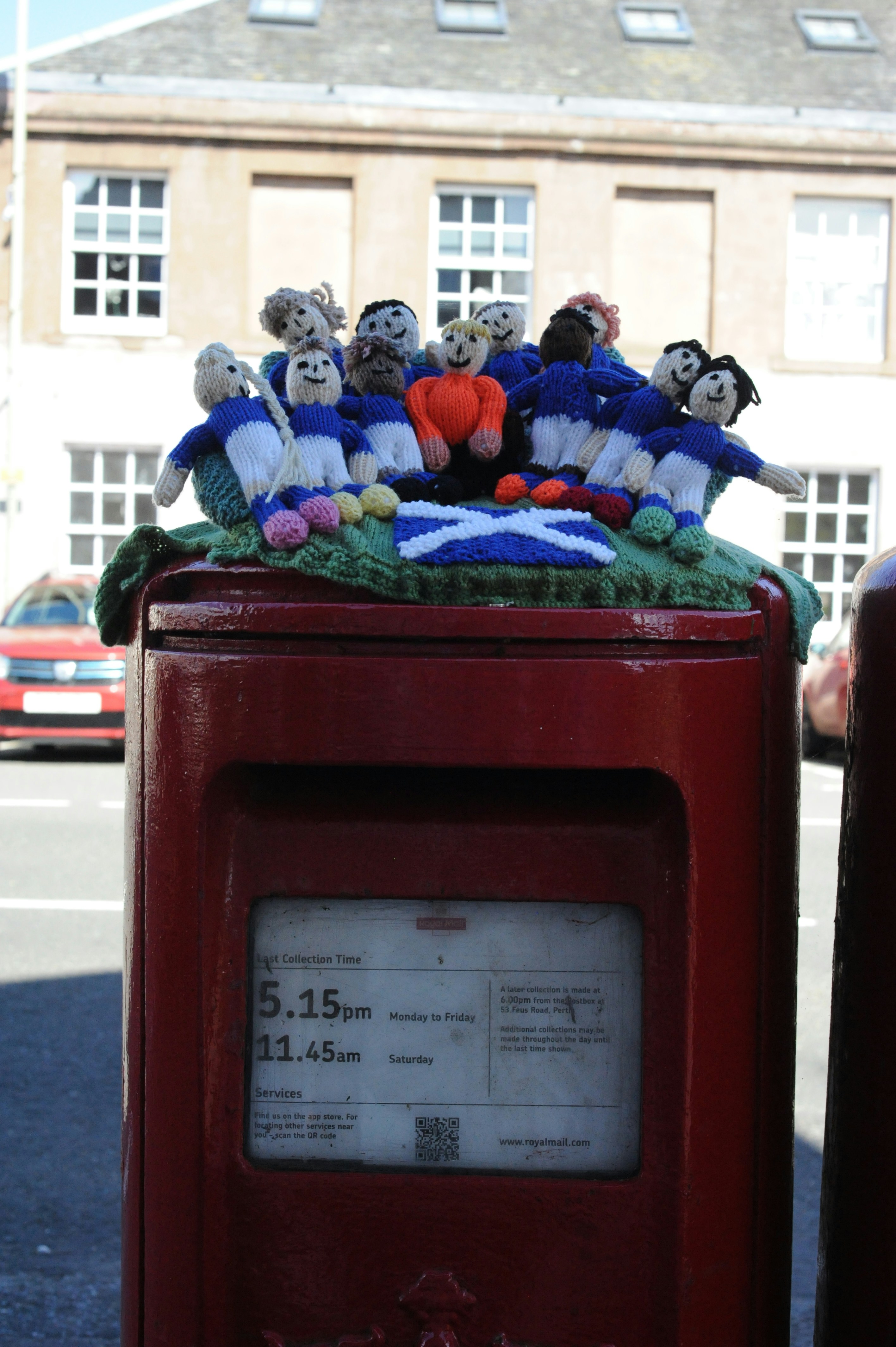Sock-top Parade on a Red Post: A Row of Handcrafted Figures Crowning a Street-Side Treasure