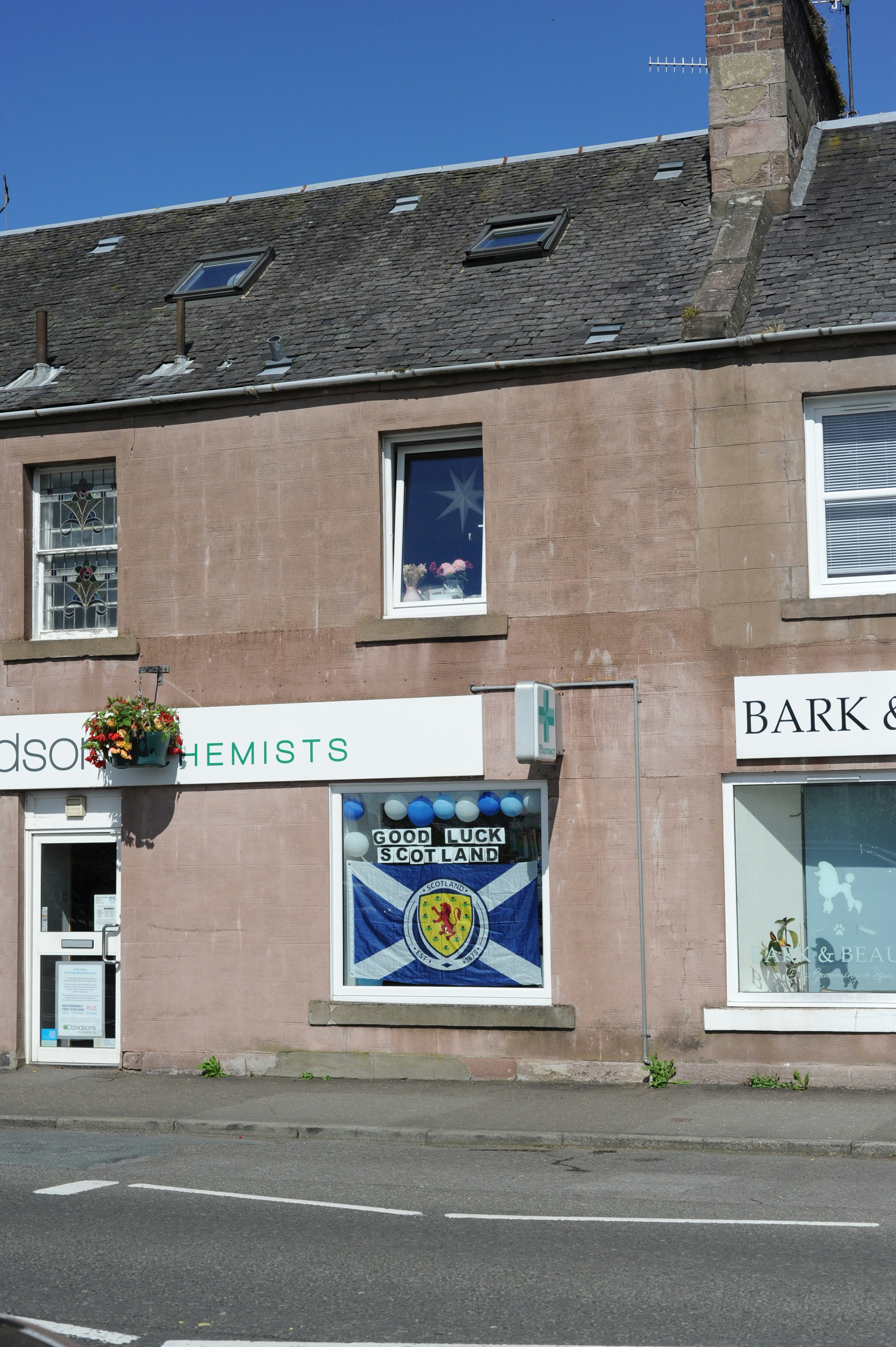 Sunlit Streetfront: A Chemists and a Banner Window