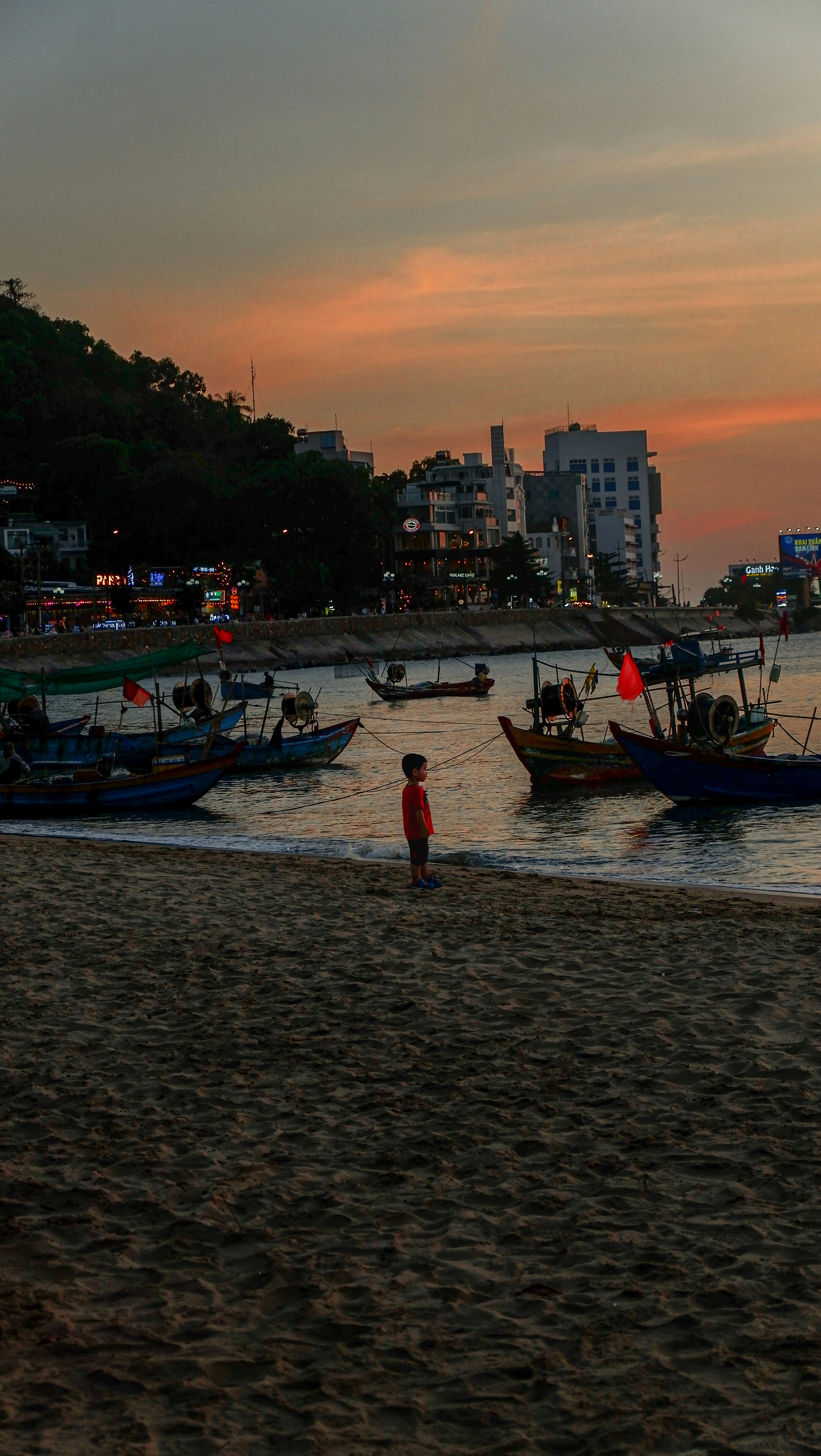 Child at the Water’s Edge Under a Sunset Harbor