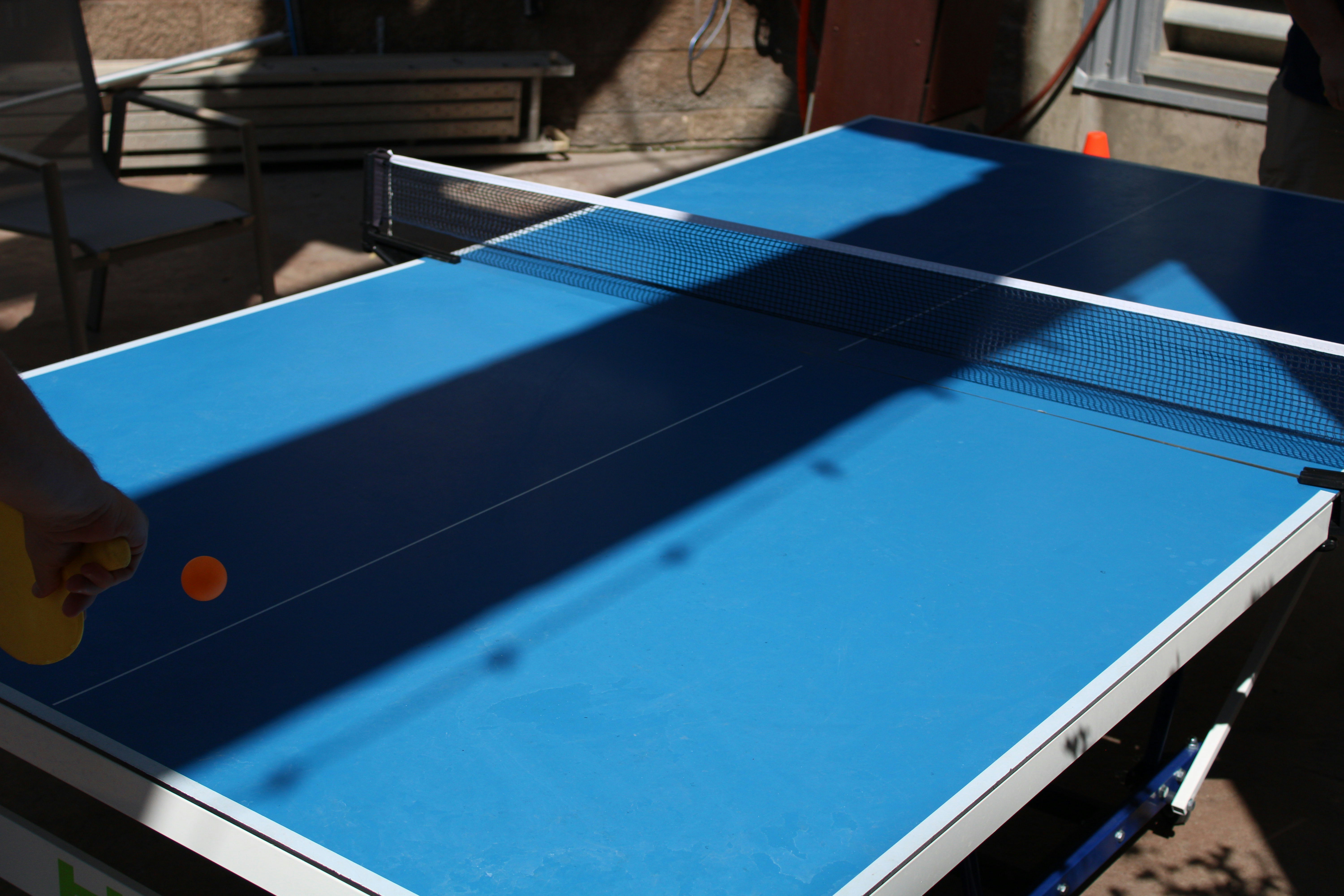 Shadowed Return: A Blue Ping-Pong Table in Afternoon Sun