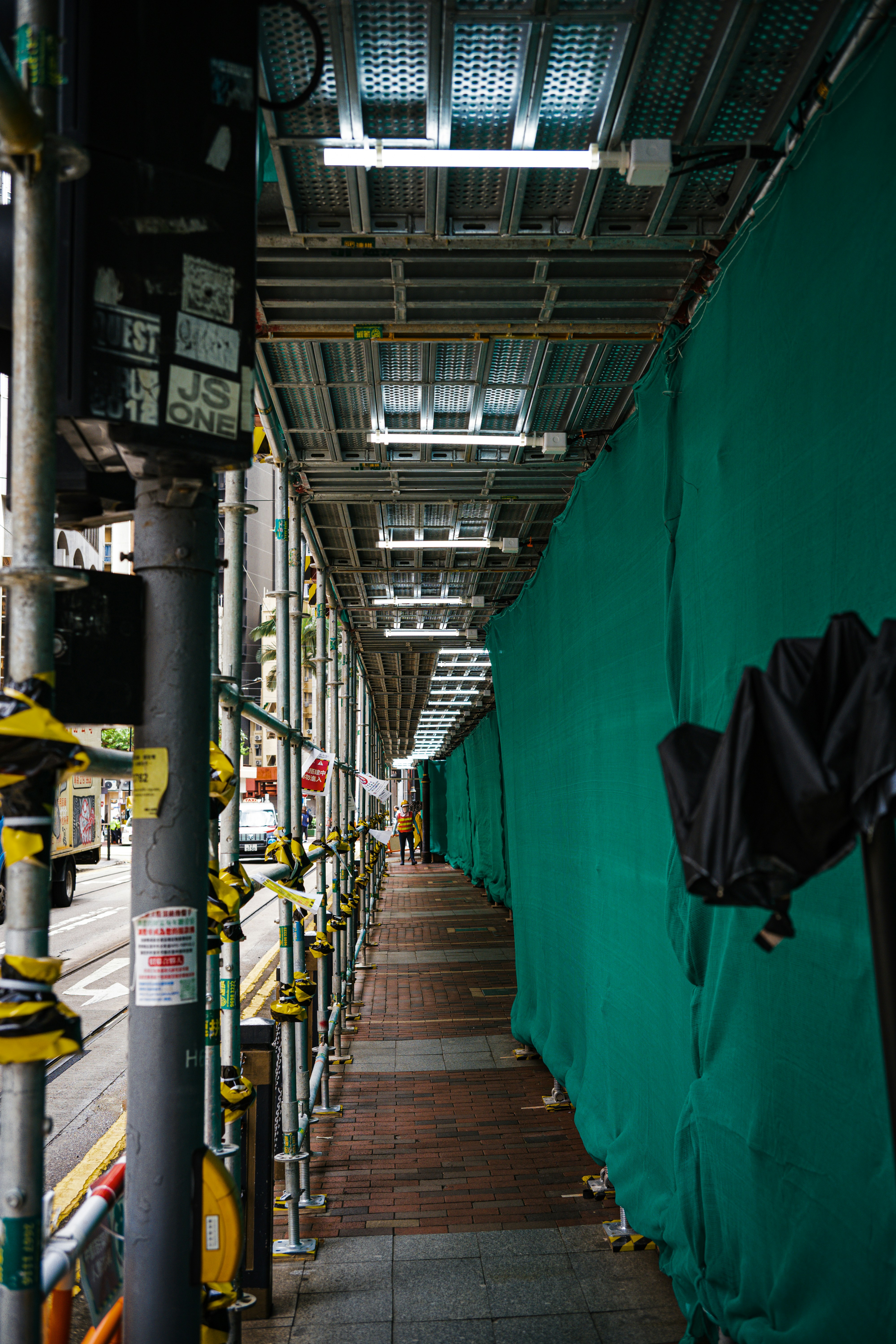 Under the Green Scaffold: A Narrow Urban Corridor of Construction Light