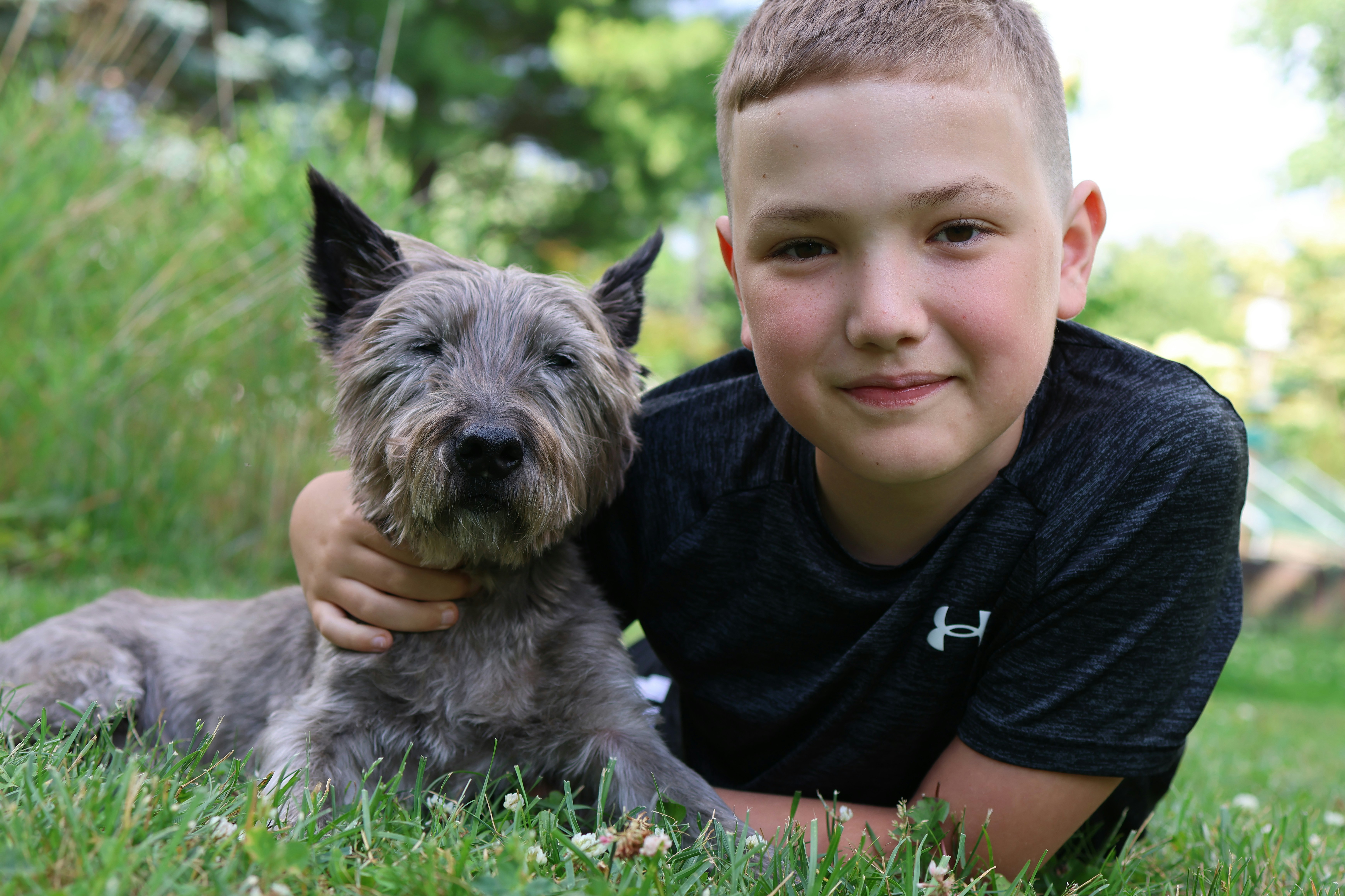 Lifelong Pals: Boy and Terrier Share a Quiet Moment on the Lawn