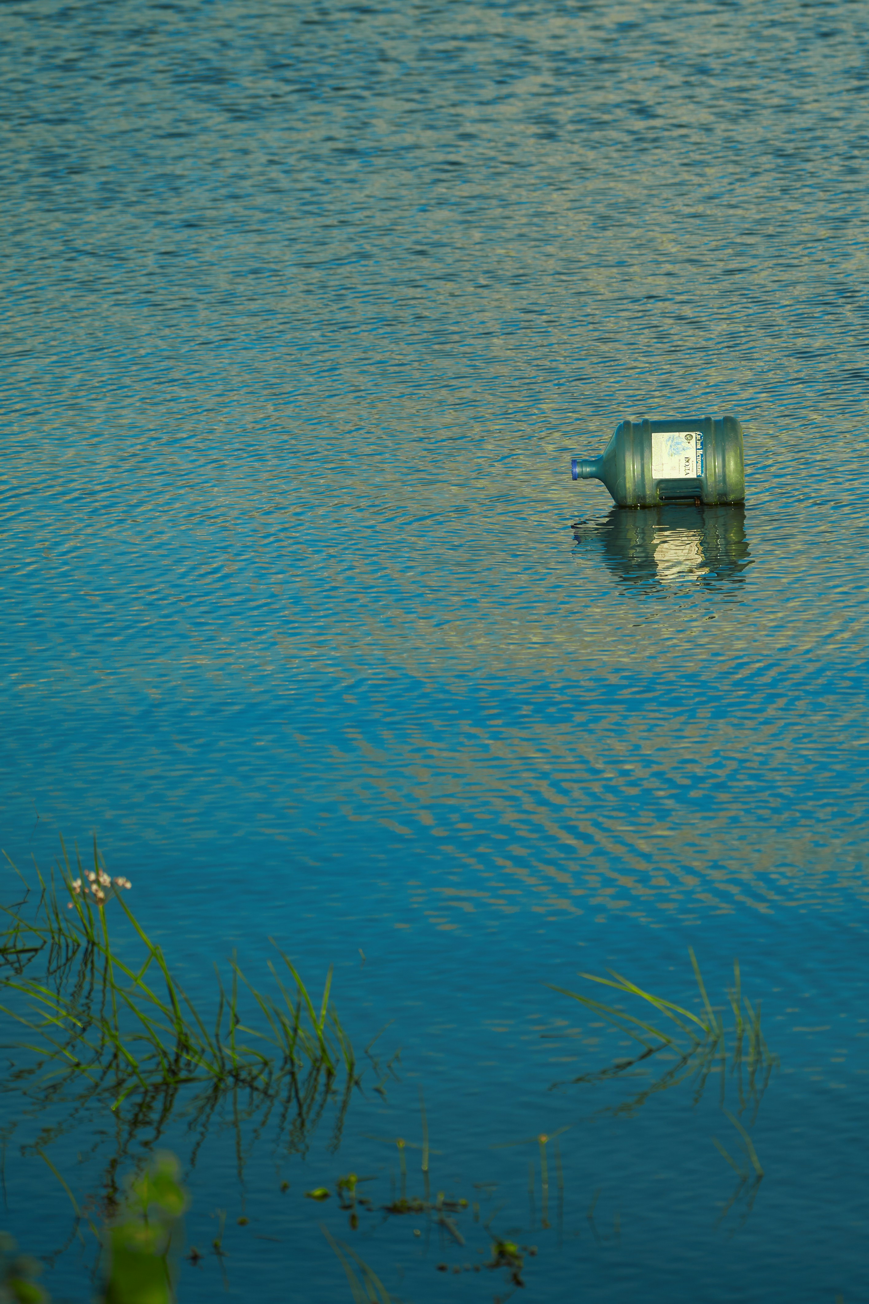 Floating Reservoir Echo: A Green Cylinder on Quiet Water