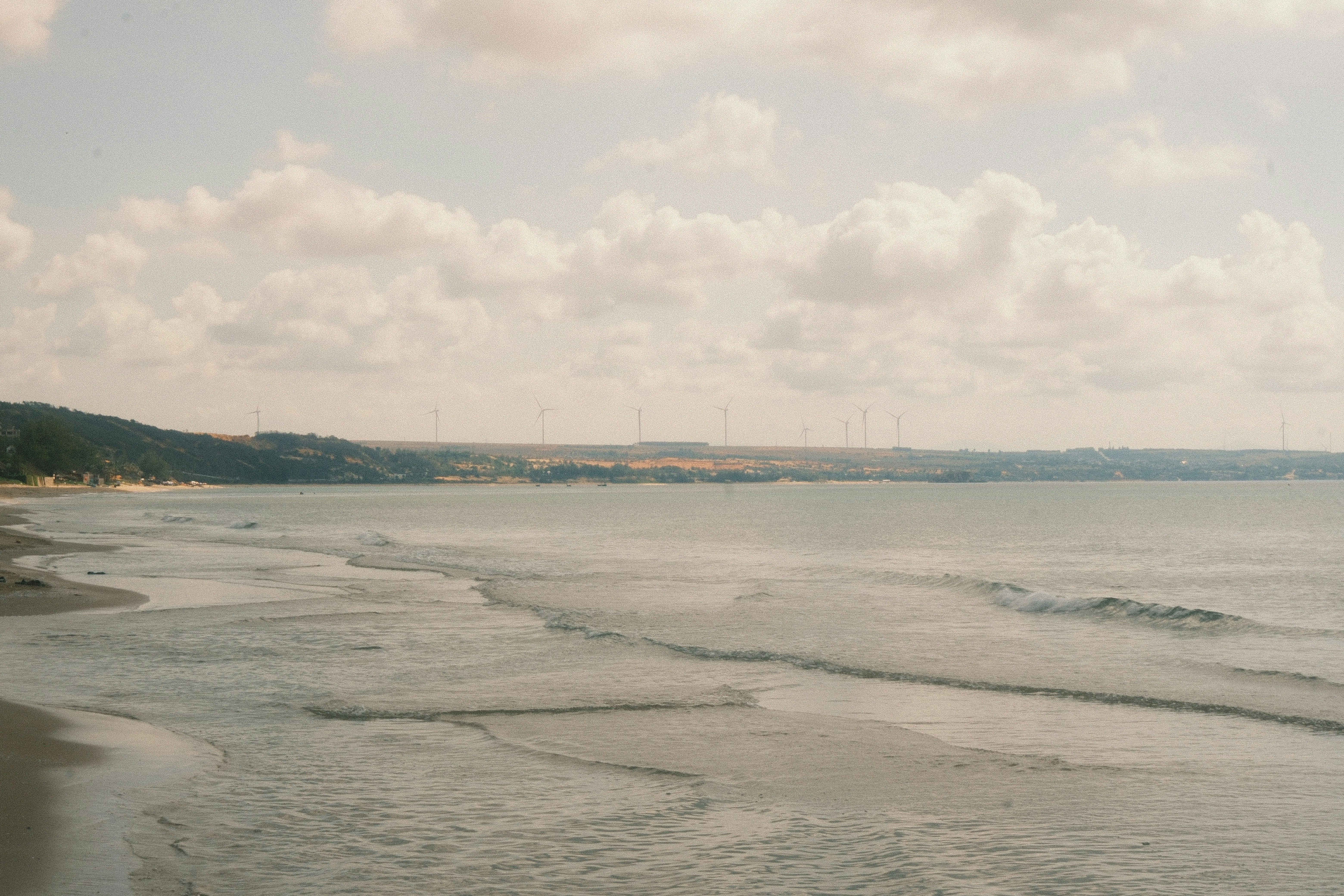 Low Tide Horizon: Wind-Scarred Beach Scene with Distant Wind Turbines