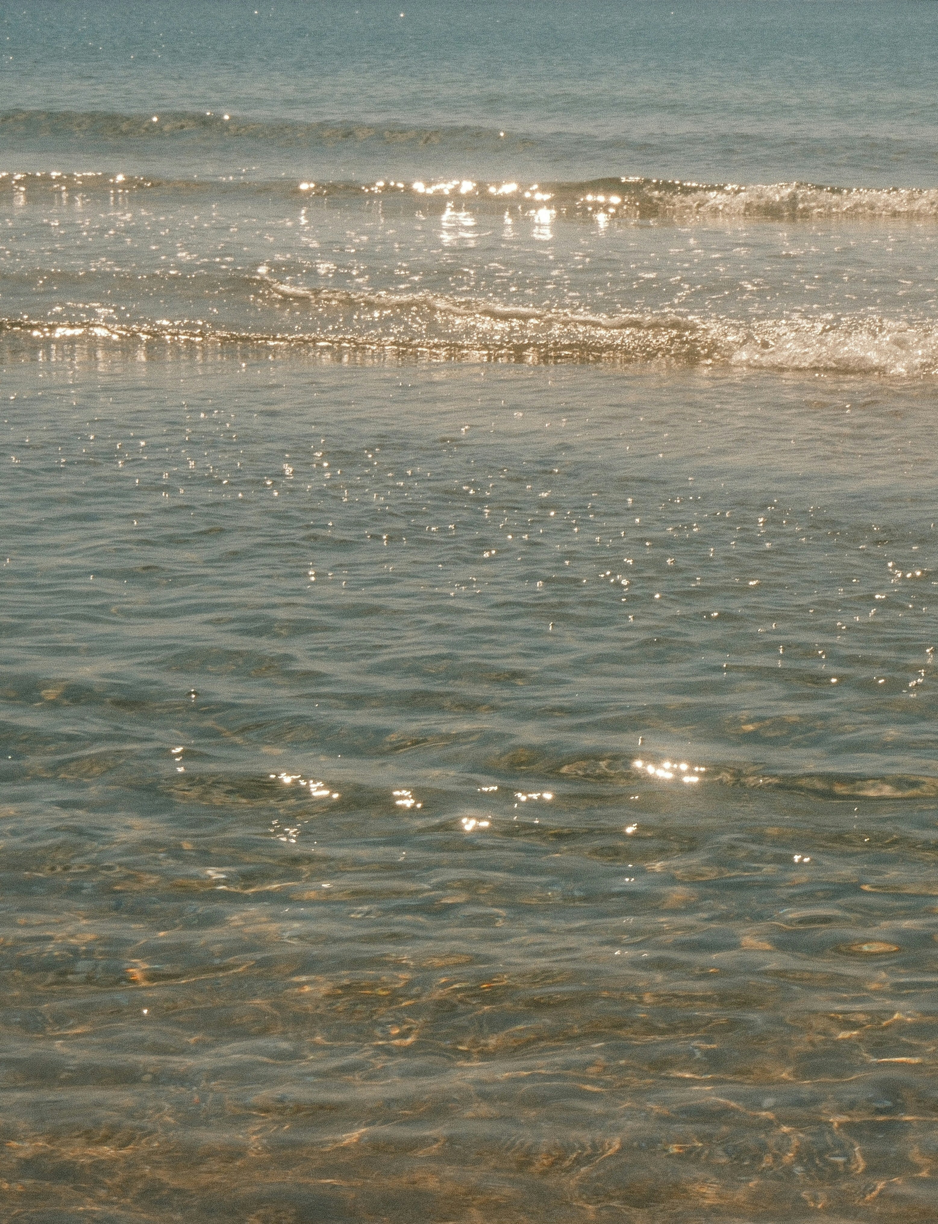Glittering Shoreline: Sunlit Ripples on Quiet Sea