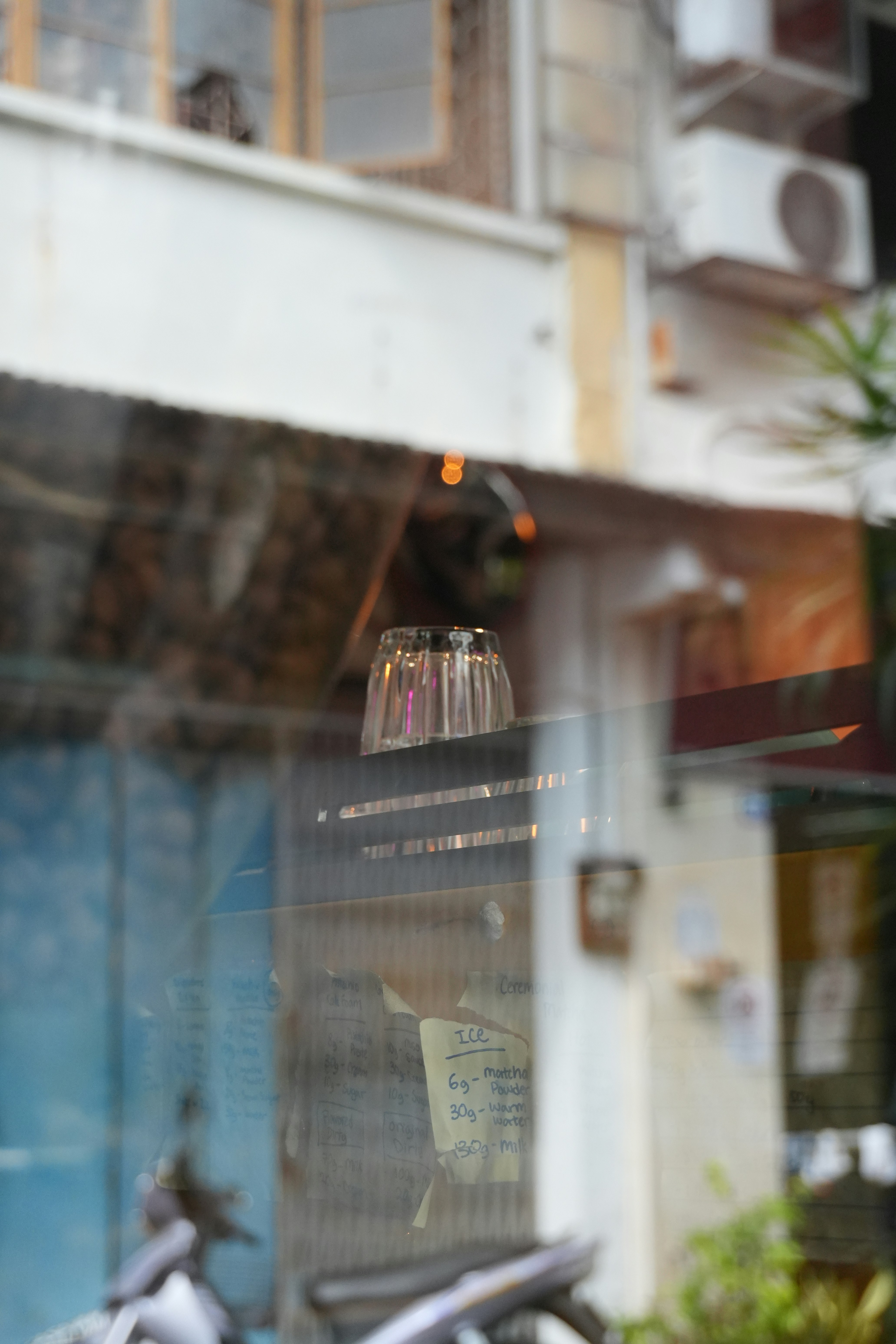 Vase in Glass: Reflections and Street Commerce Through a Café Window