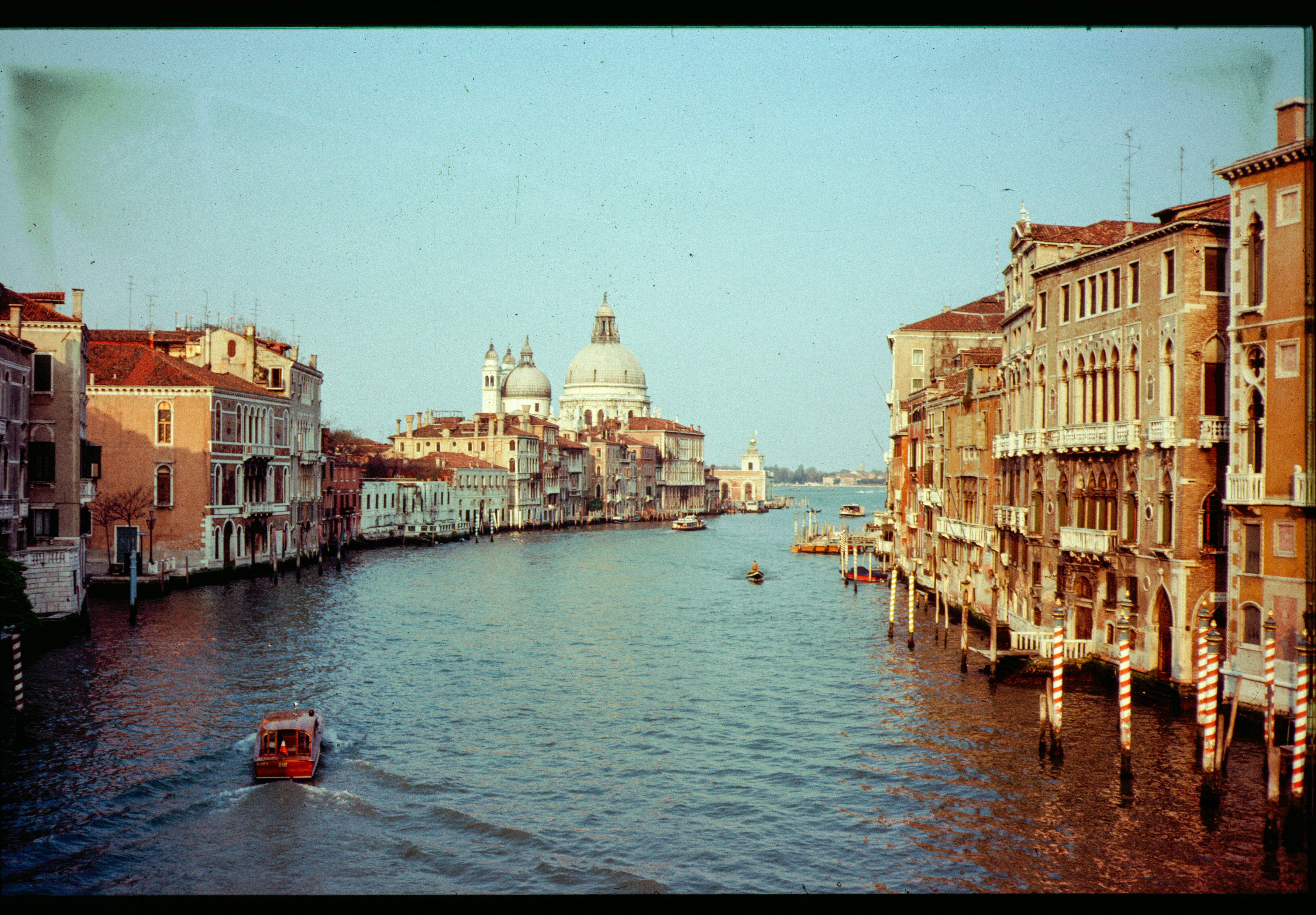 Venetian Canal Aglow: Boats, Facades, and a Distant Domed Skyline