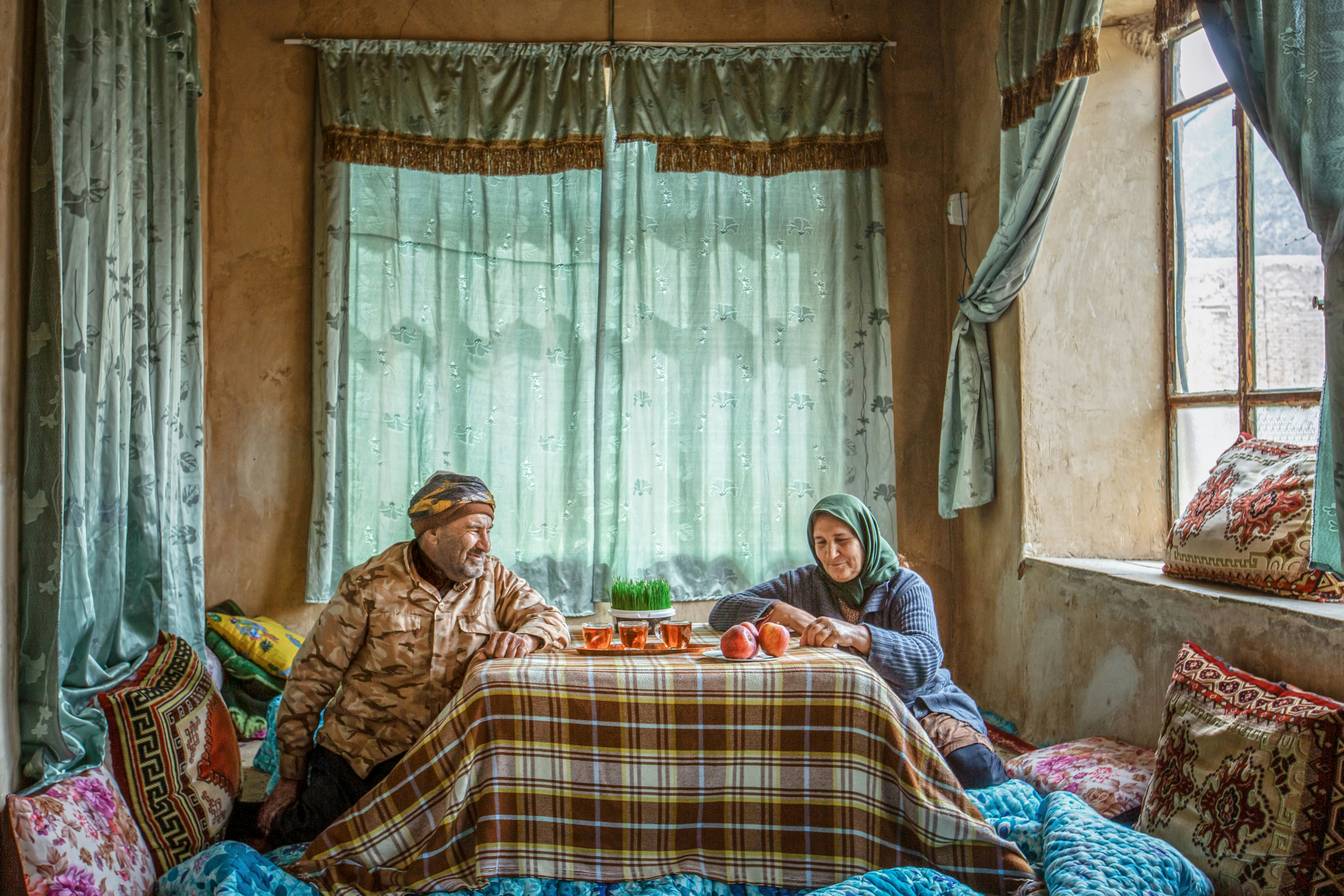 Tea at the Low Table: Quiet Conversation Between Two in a Cozy, Tarnished Room