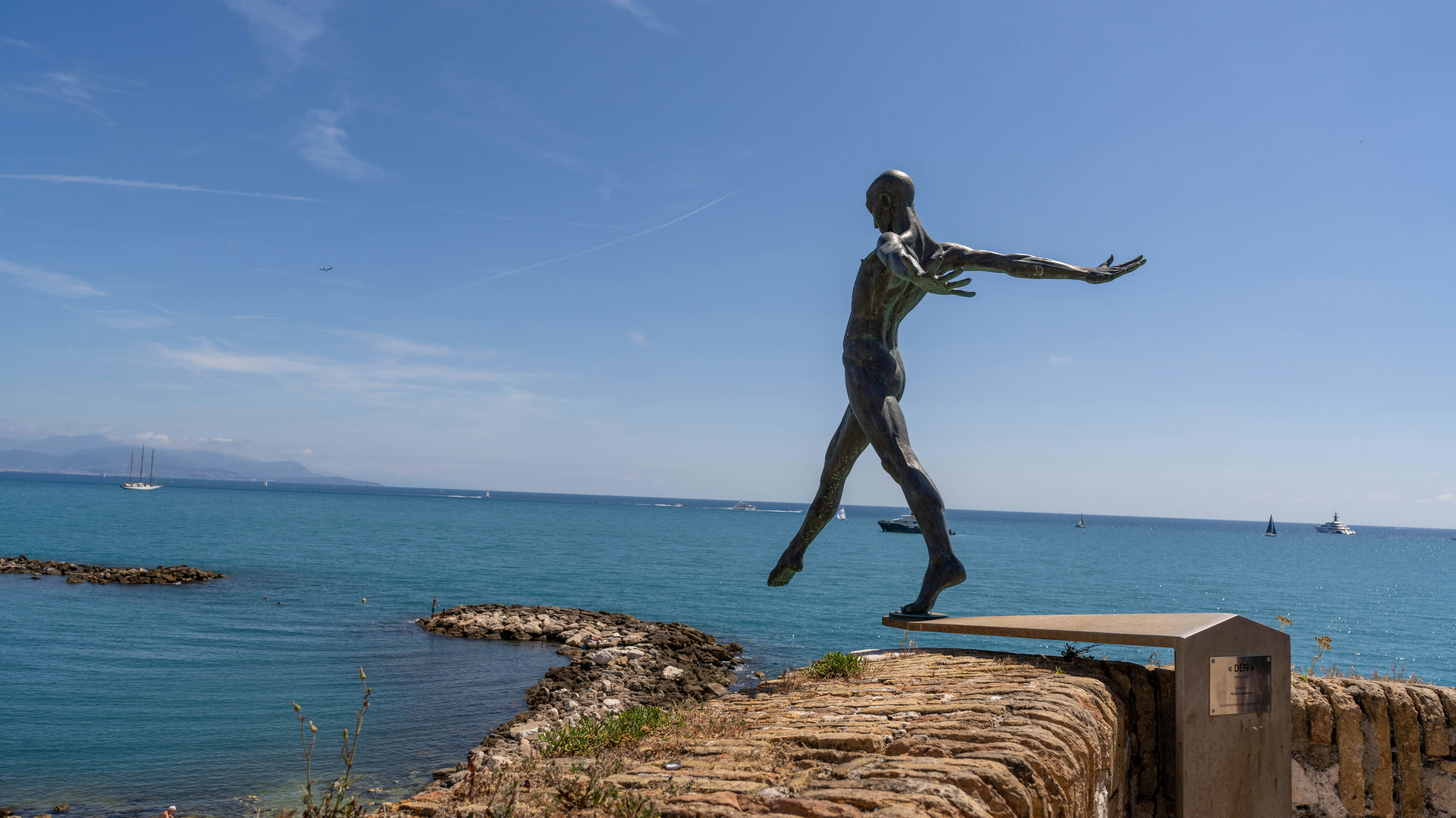 Balancing on the Sea: Bronze Figure Poised at Cliff Edge