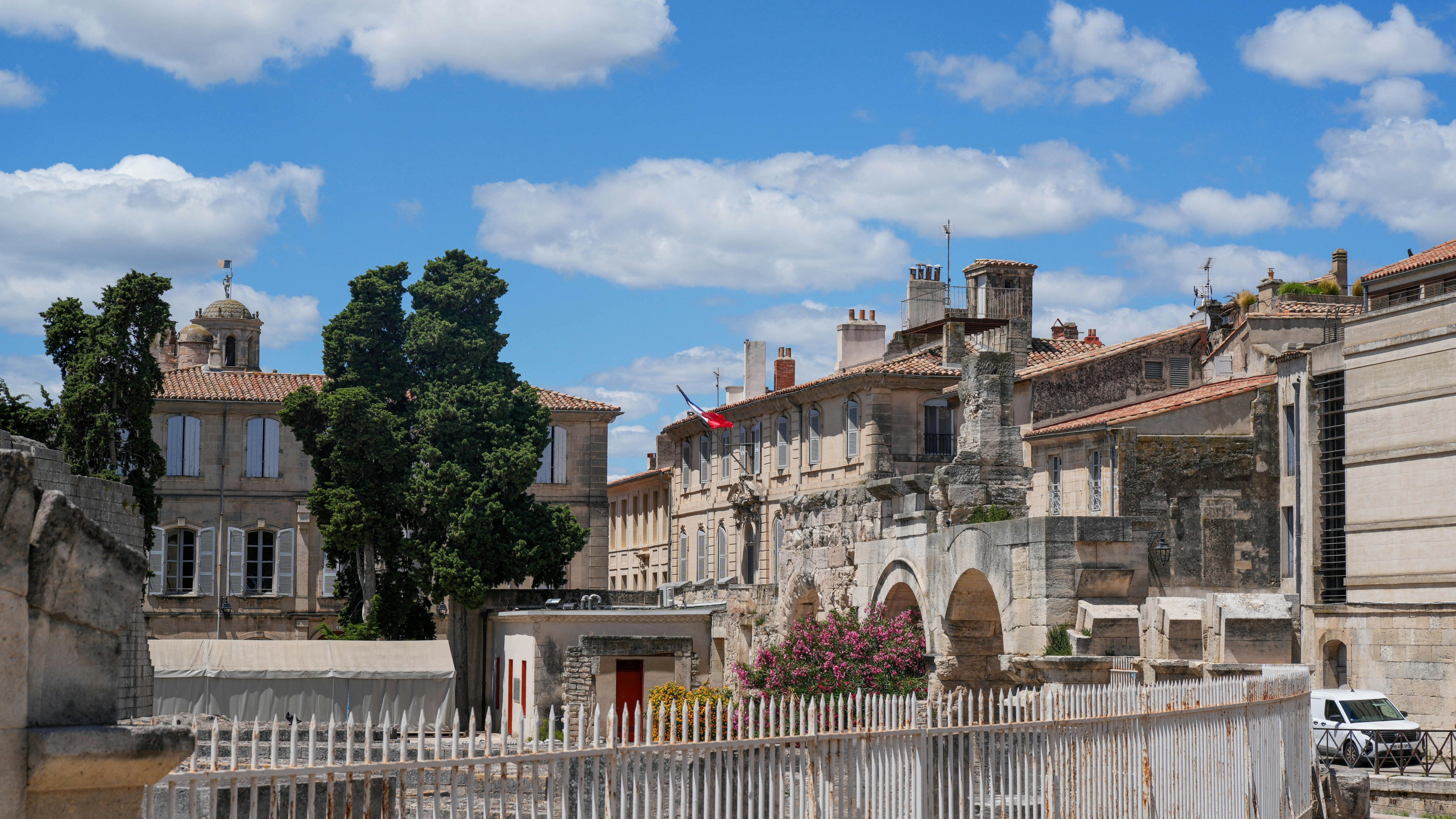 Sunlit storefronts and arches along a Provençal hillside street