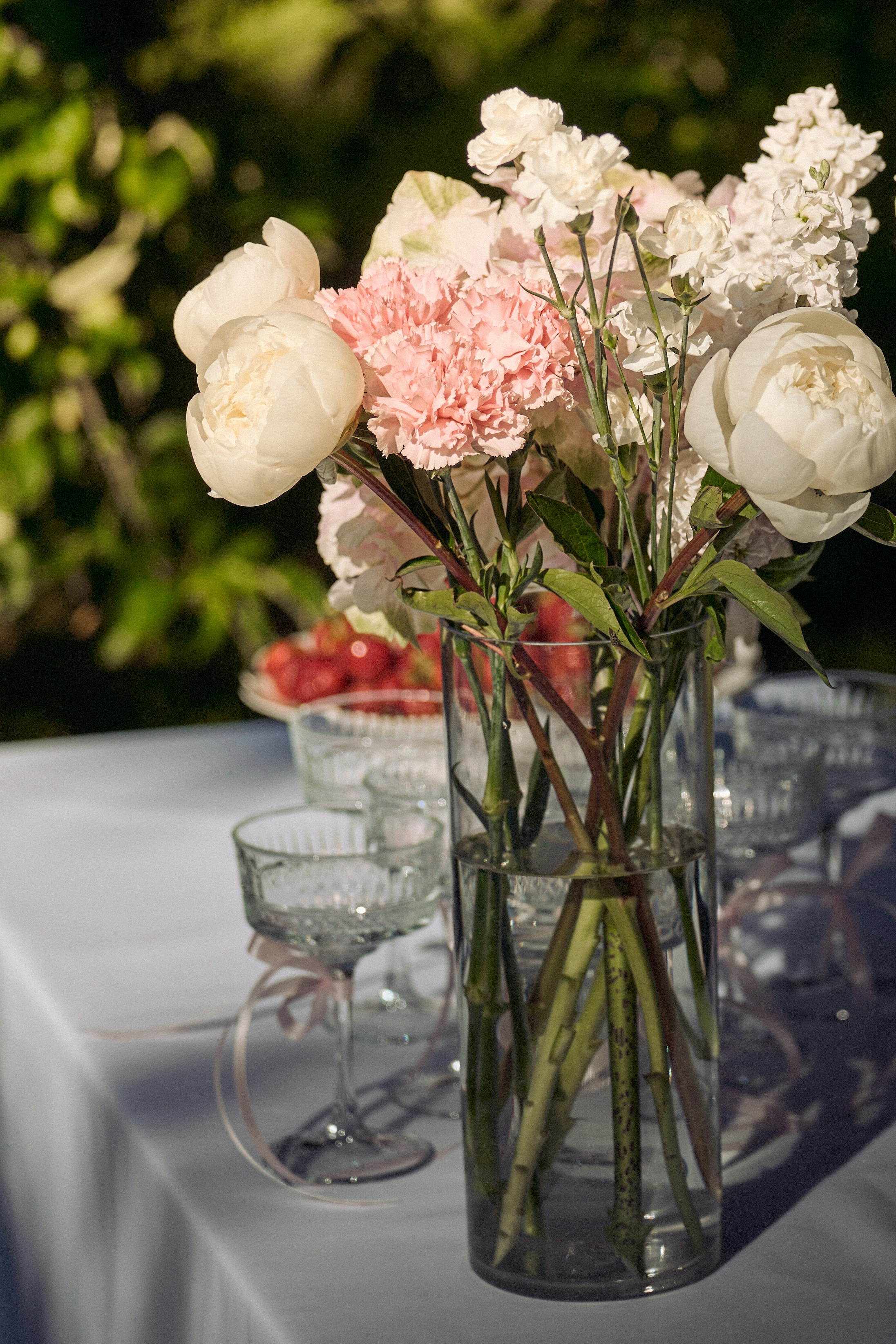 Soft pastel bouquet centerpiece in glass vase on sunlit banquet table