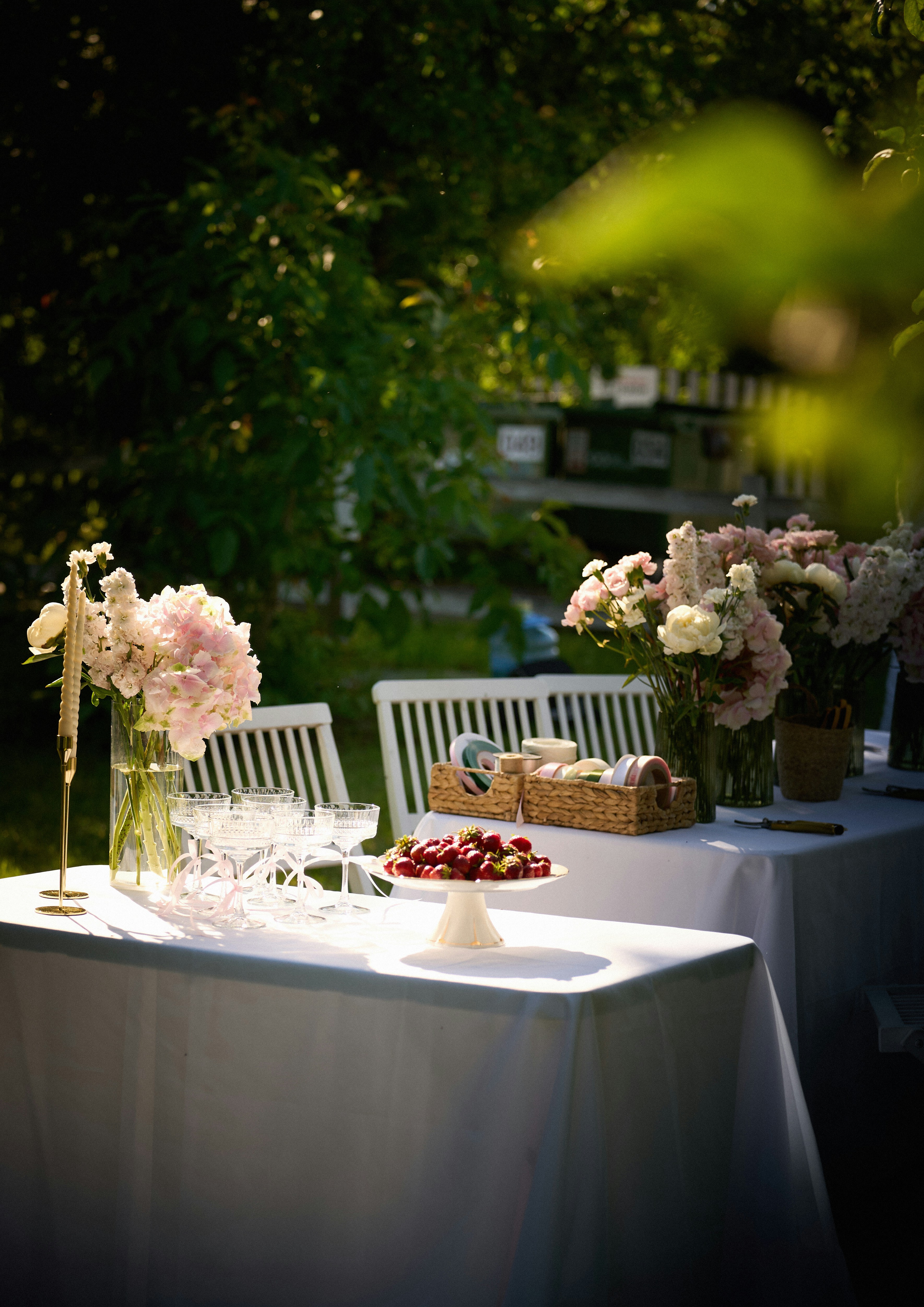 Sunlit dessert table framed by soft florals under dappled garden light